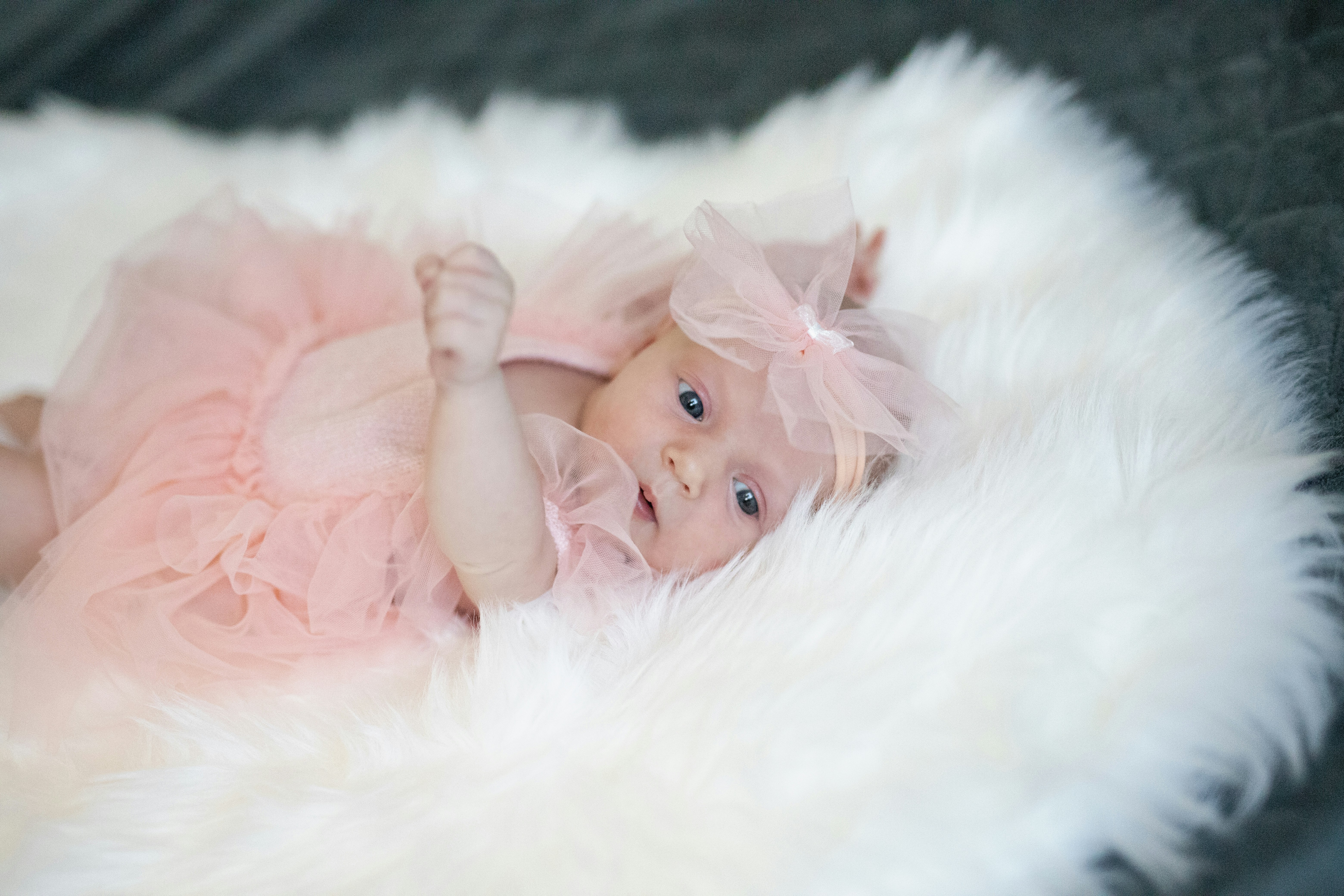 A baby in a pink dress laying on a fluffy white blanket photo – Free ...