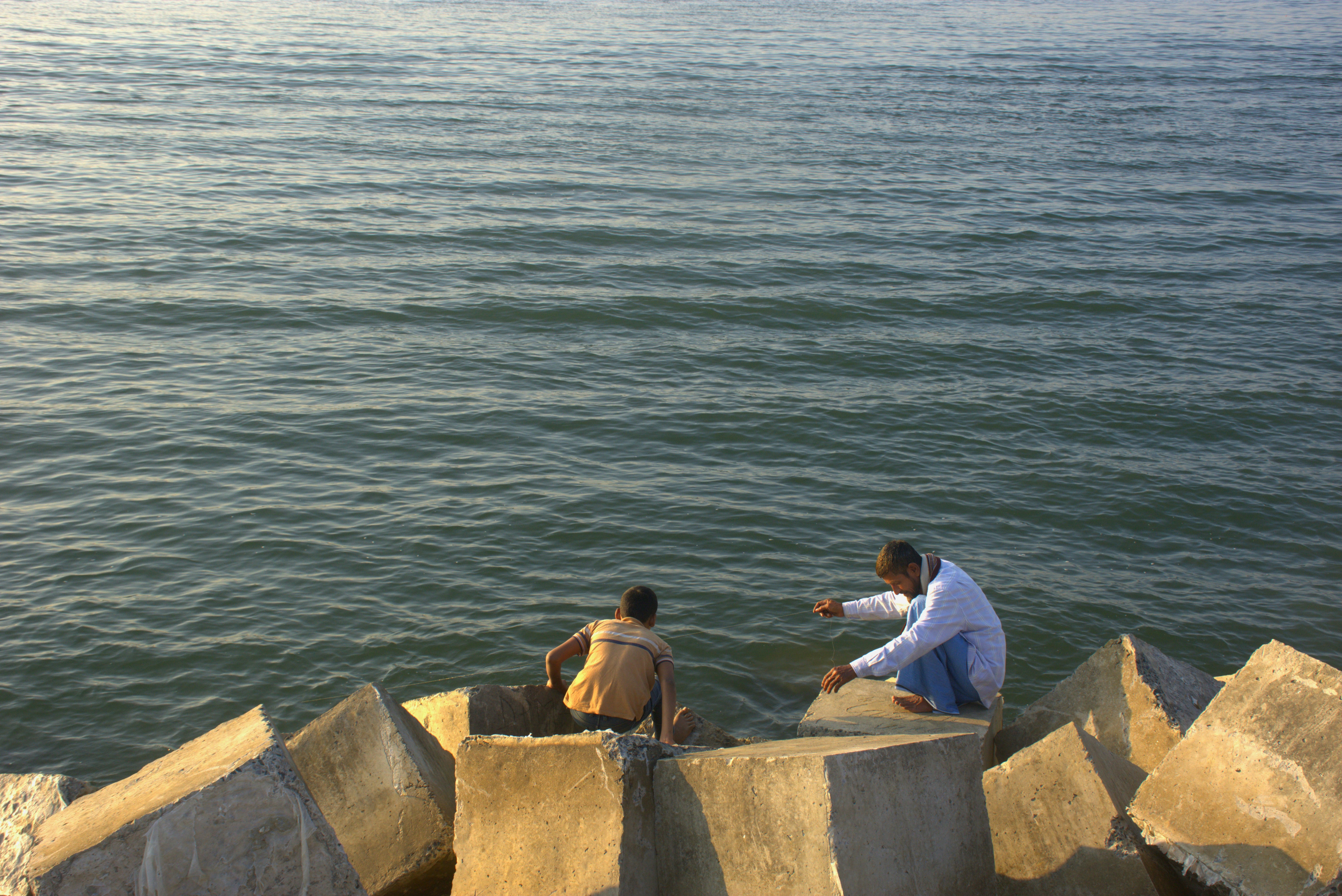 Breakwater Dialogue: Two Figures on Concrete Blocks by the Sea