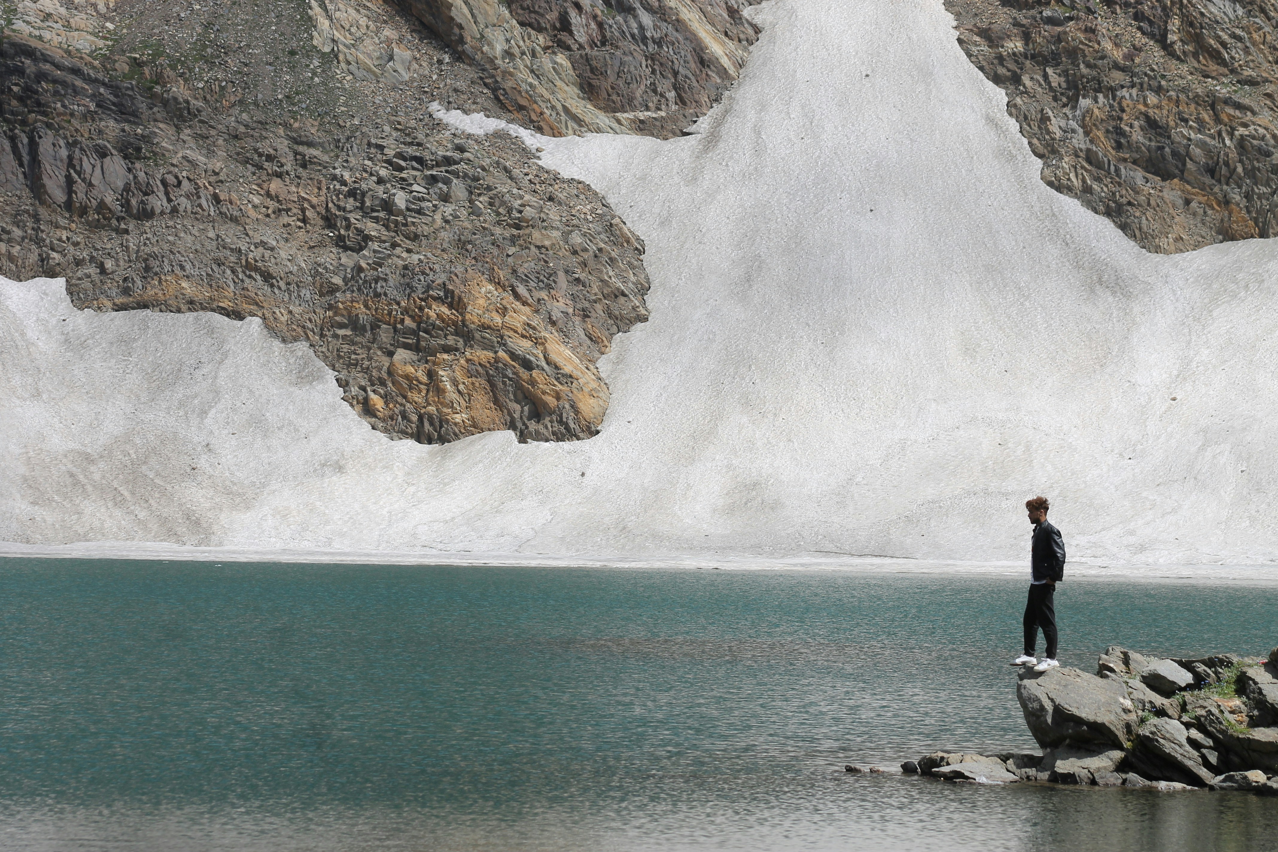 Threshold of Glacier Snow and Turquoise Stillness: A Lone Figure by the Lake