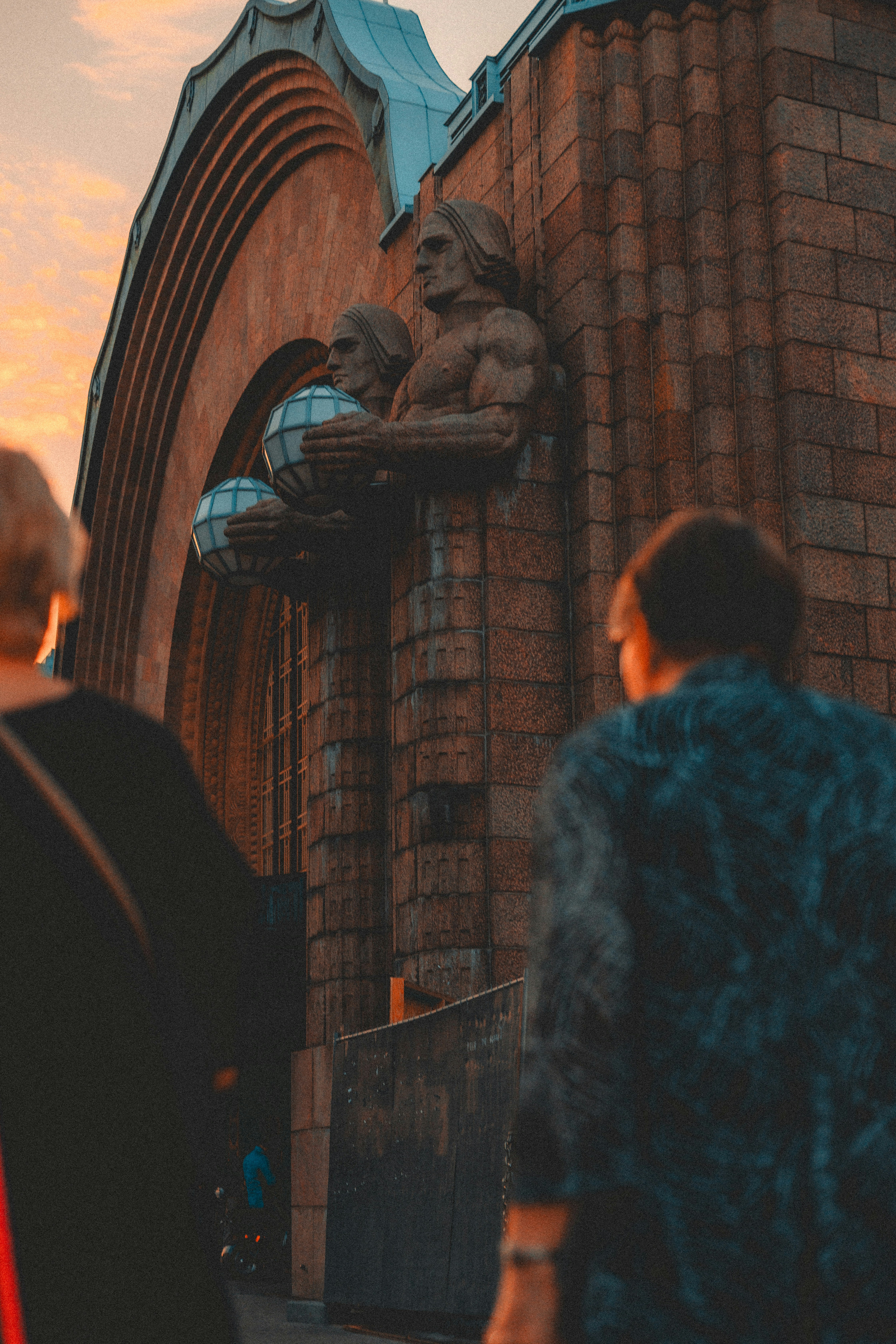Archway Guardians at Dusk: Stone Figures Over a Quiet Street