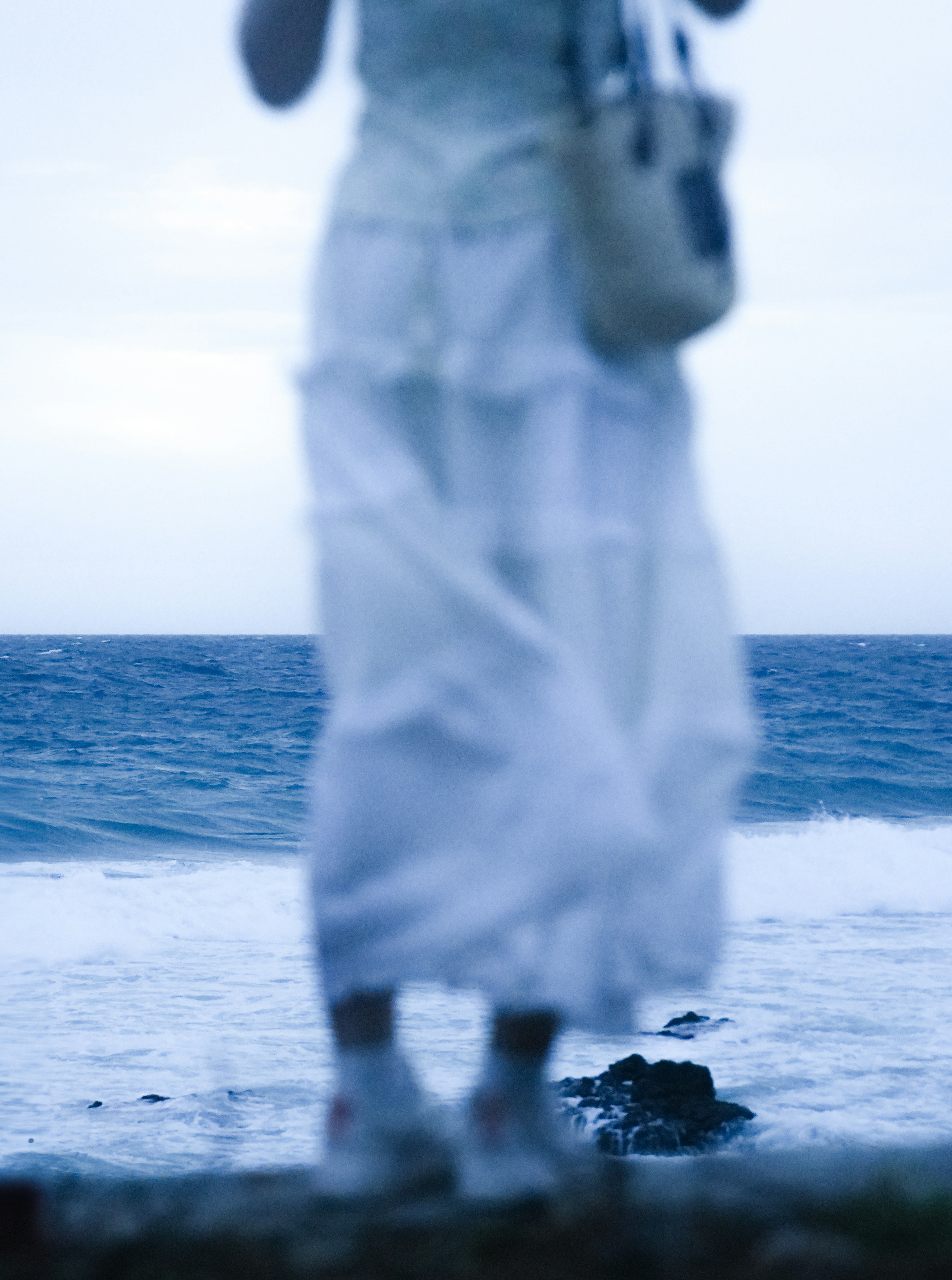 Waves Behind a Blurred Figure in a White Dress