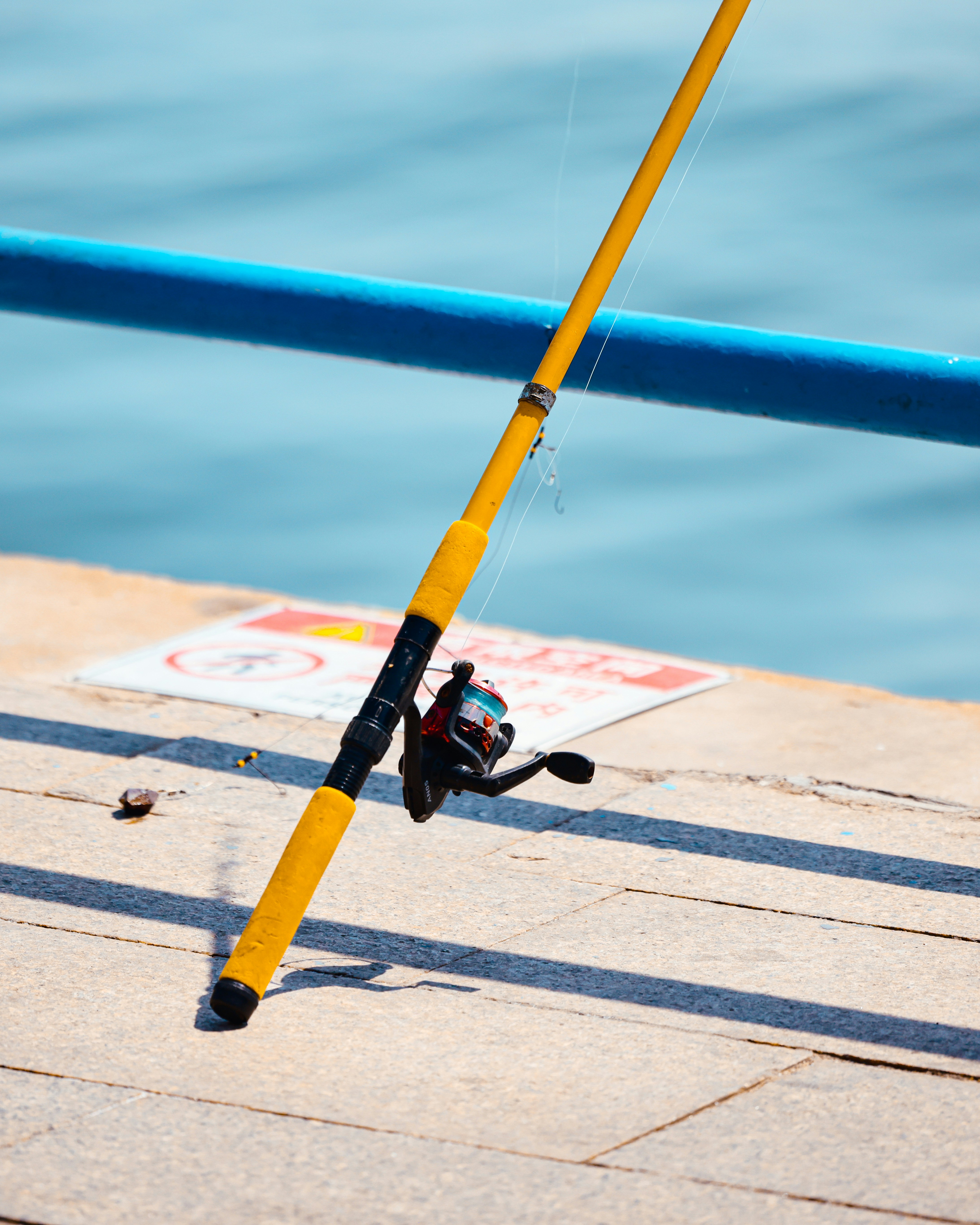 Diagonal Tide: A Yellow Rod Resting on a Seaside Pier