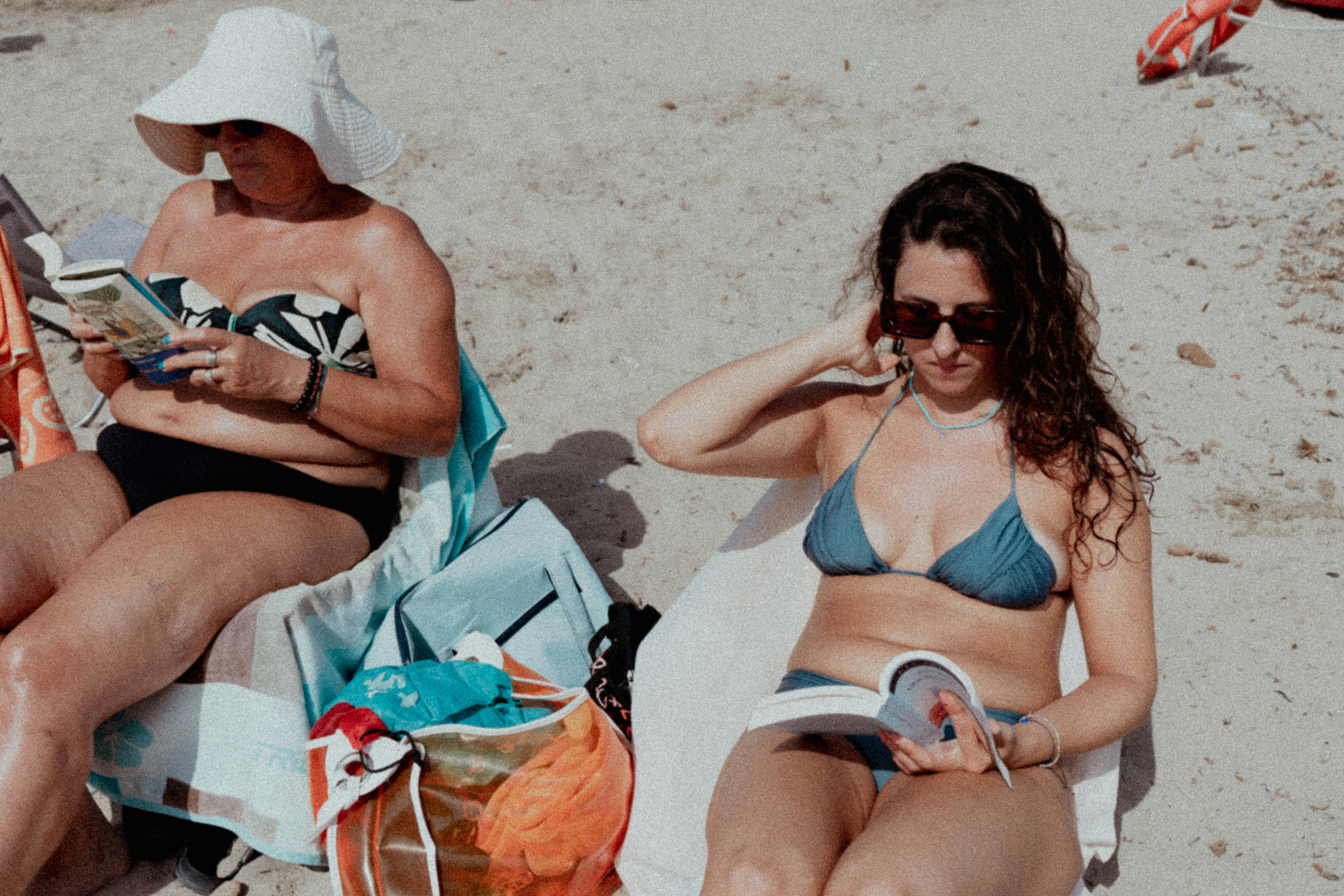 A couple of women sitting on top of a sandy beachCarmen Laezza