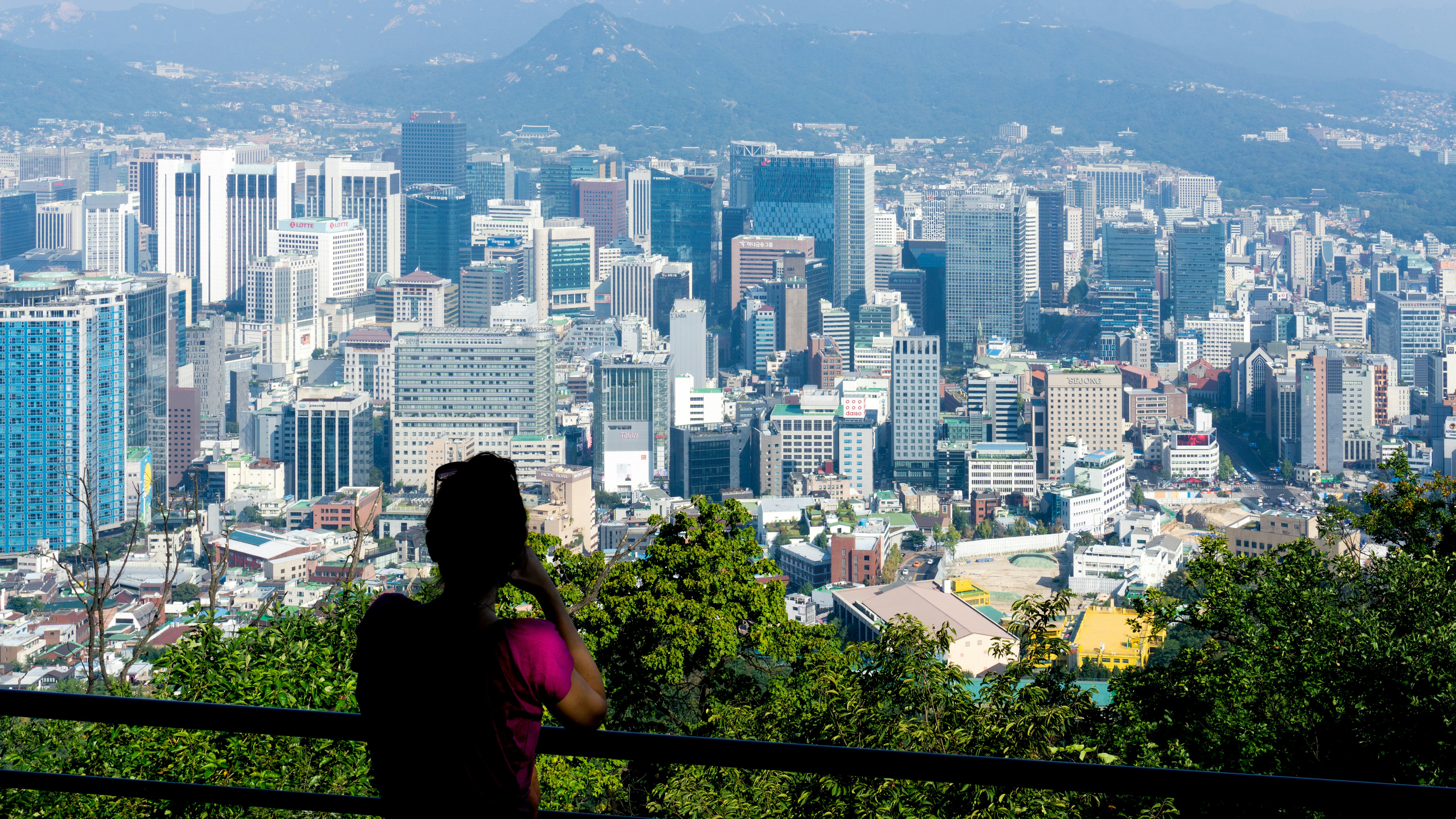 Person silhouetted against a vibrant cityscape with mountains in the background.