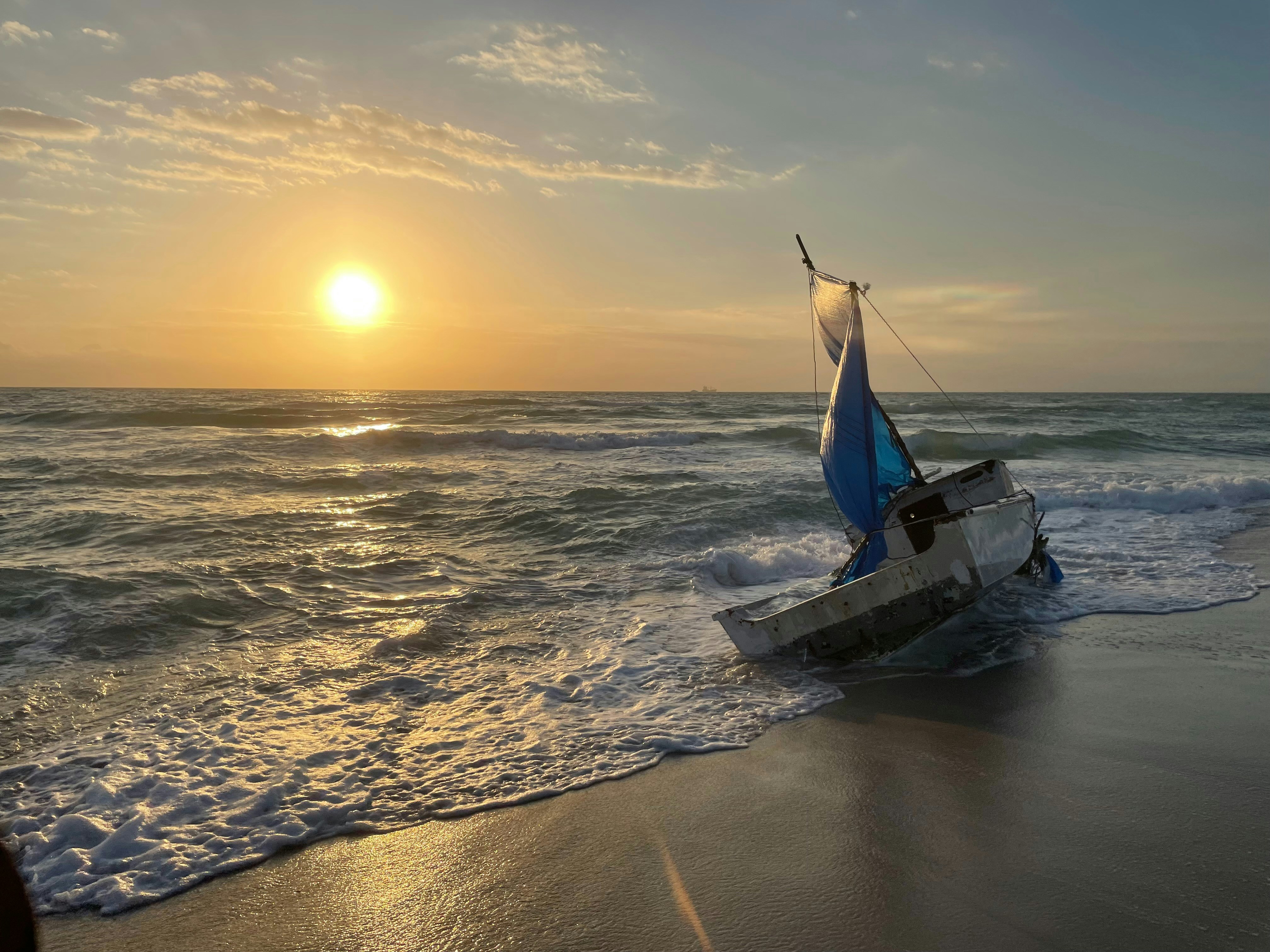 Dusk on the Shore: A Beached Sloop and the Sun's Quiet Embers