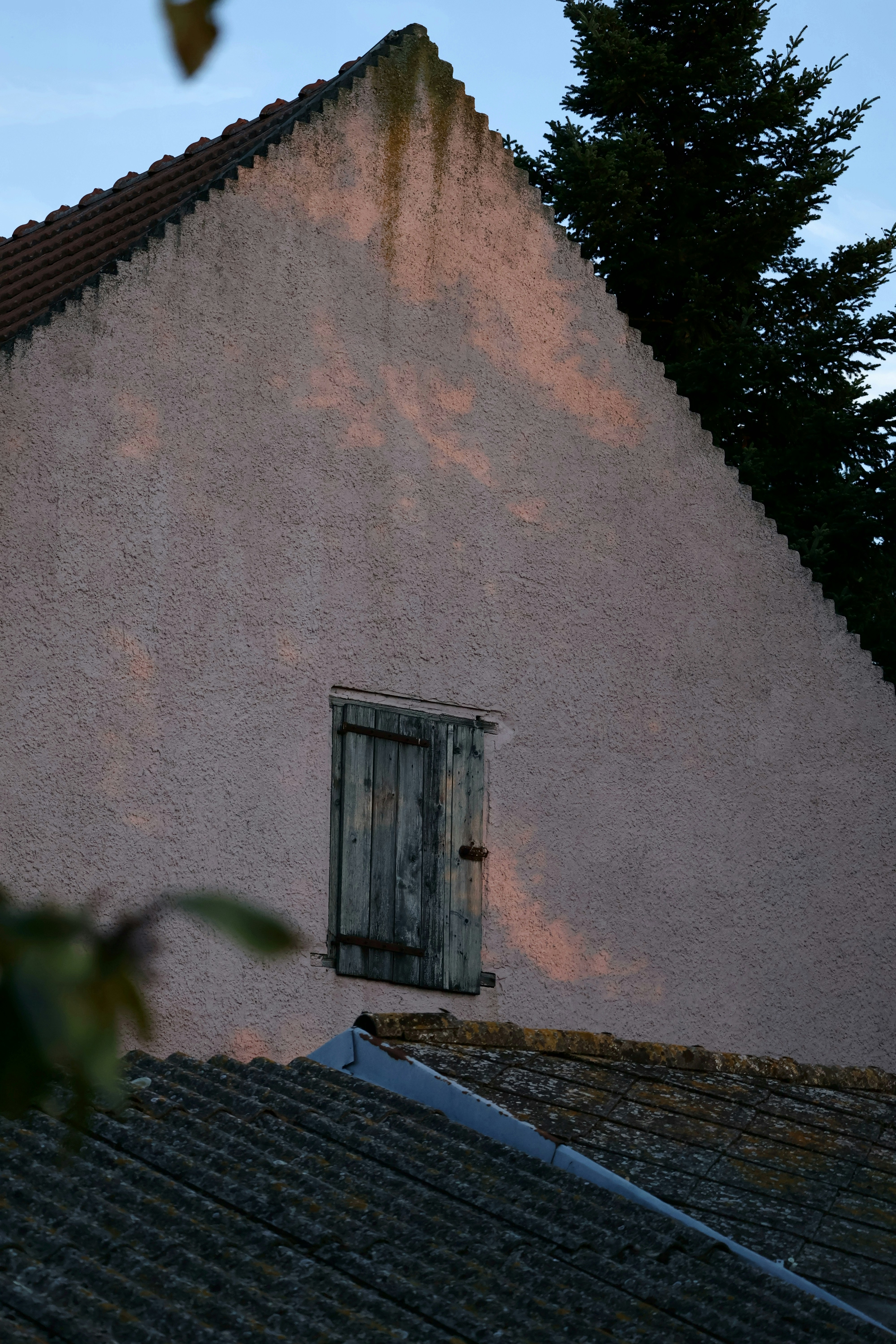Gabled Facade at Dusk: Warm Glint on a Weathered Shutter