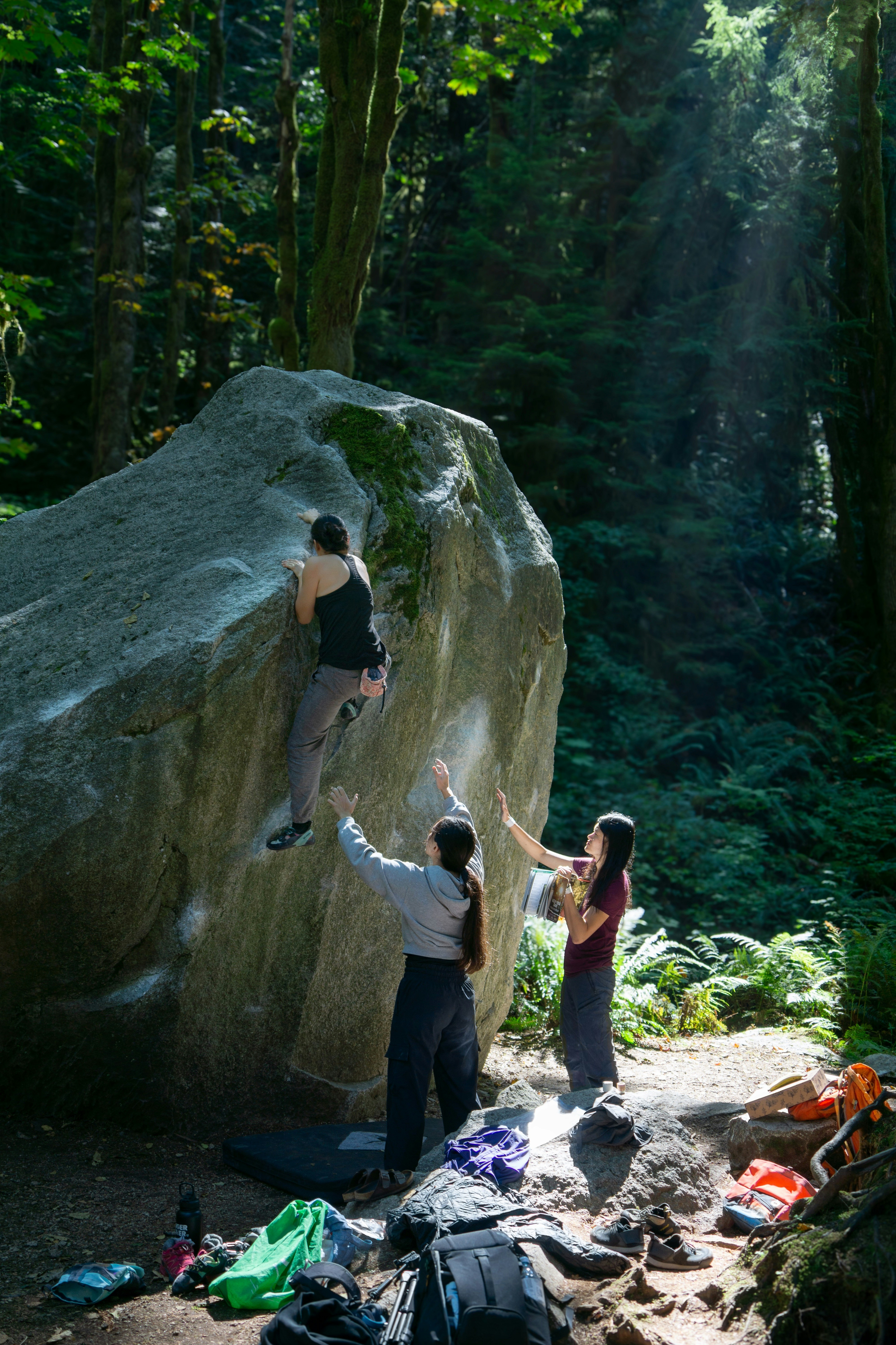 Forest Ascent: A Climber Tackles a Mossy Boulder Under Dappled Light