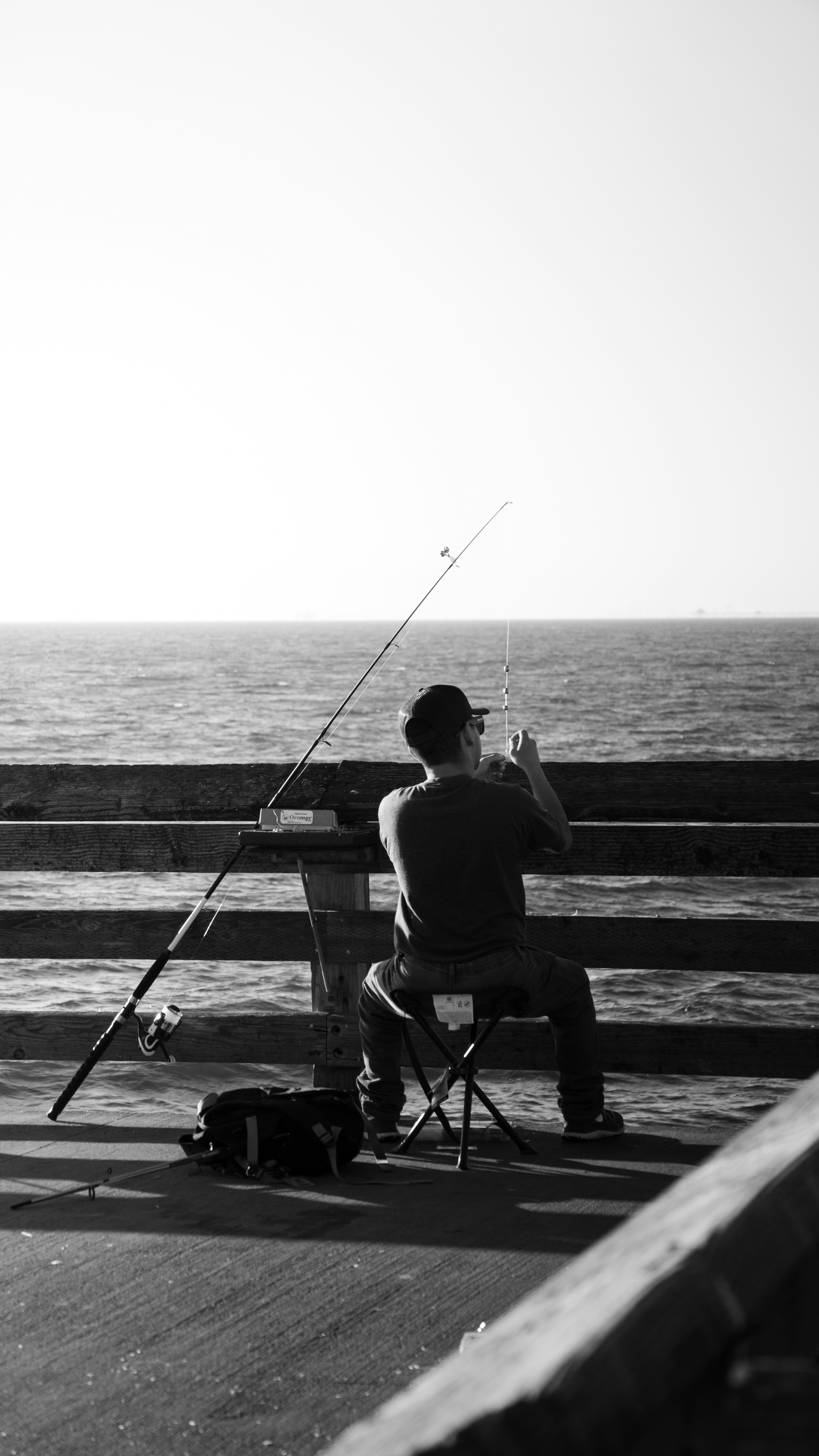 Line and Horizon: A Solo Fisherman on a Pier in Monochrome