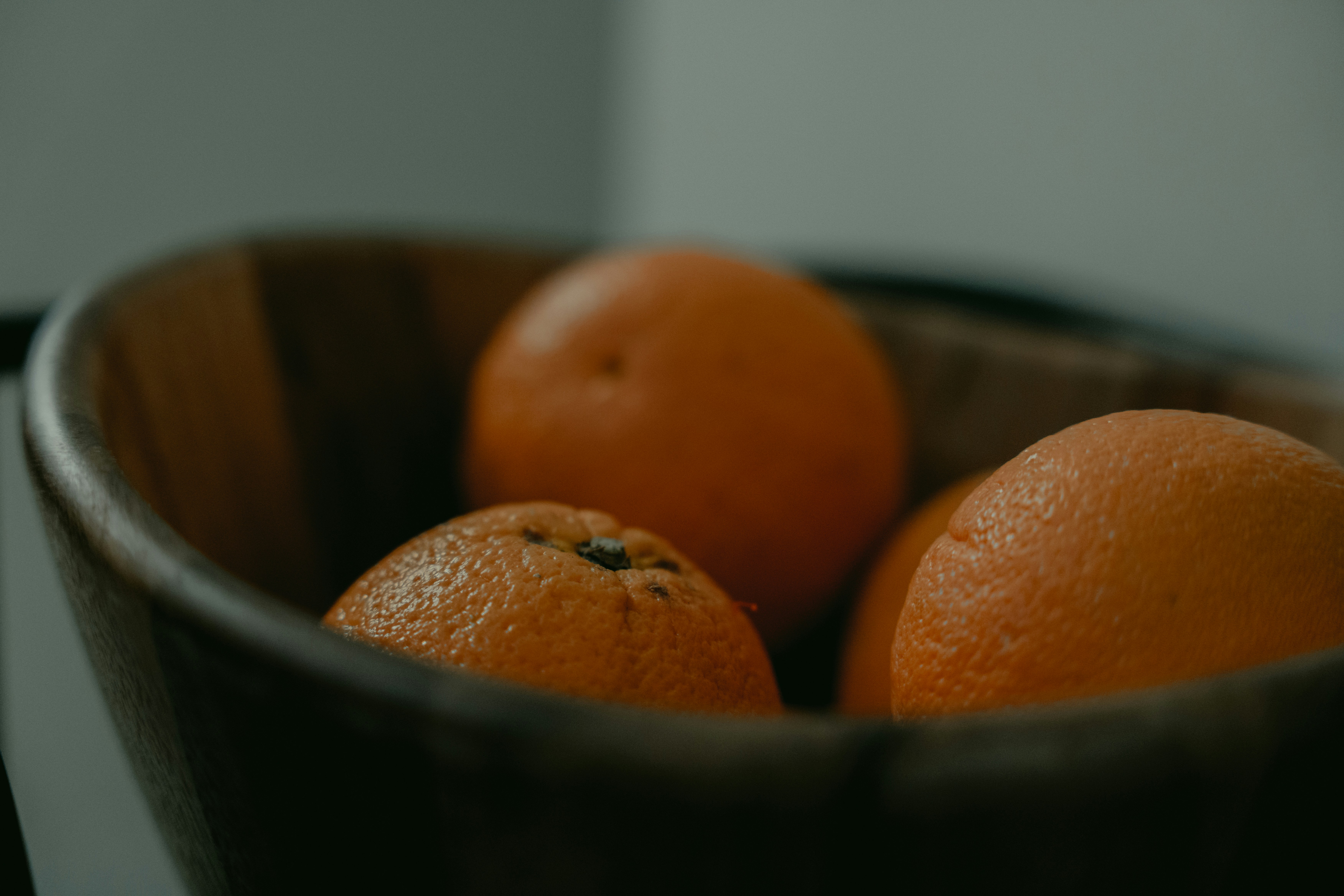 Amber Oranges Nest in a Walnut Bowl Under Soft Light