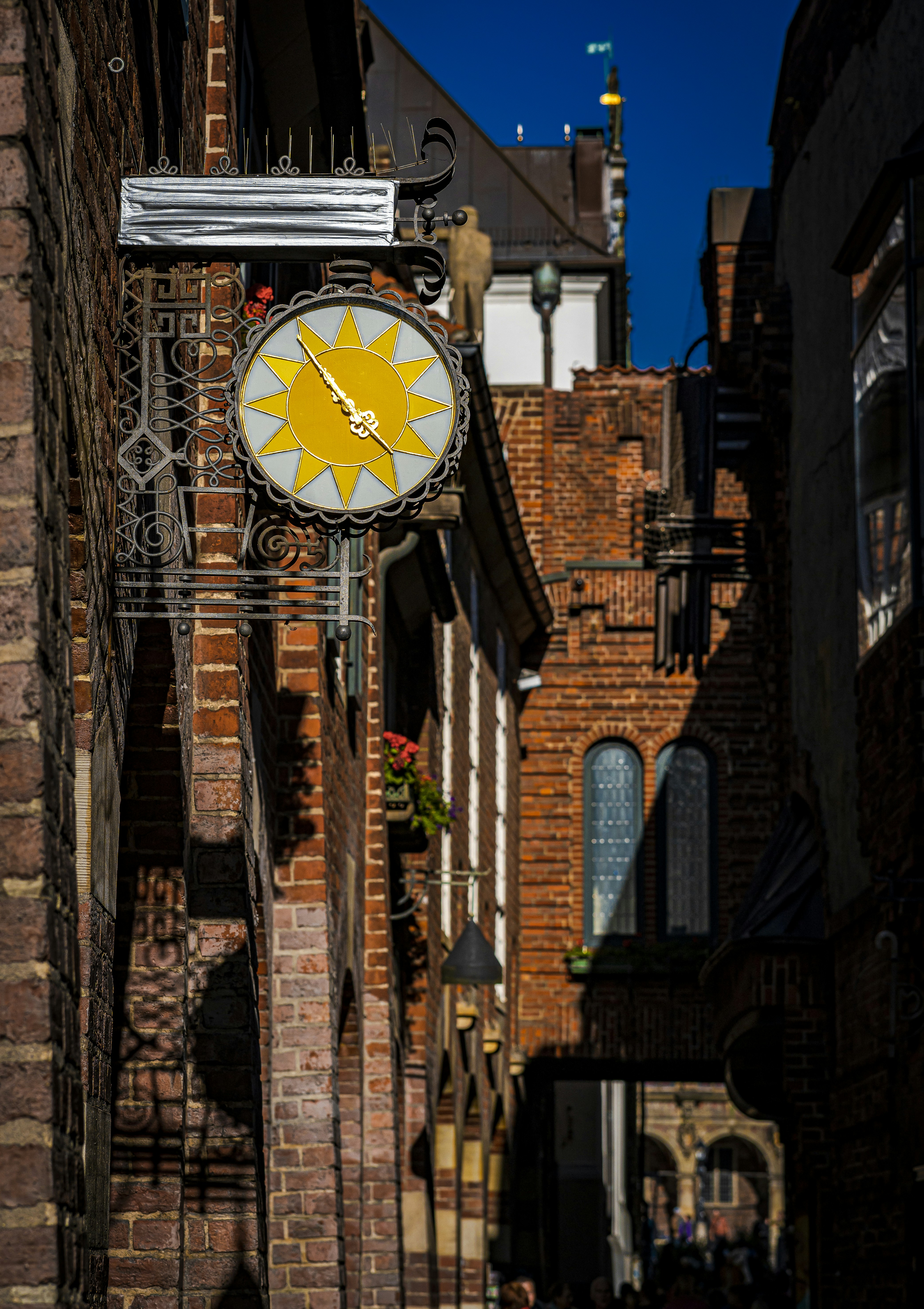 Sunburst Clock Sign Swaying Over a Narrow Brick Alley