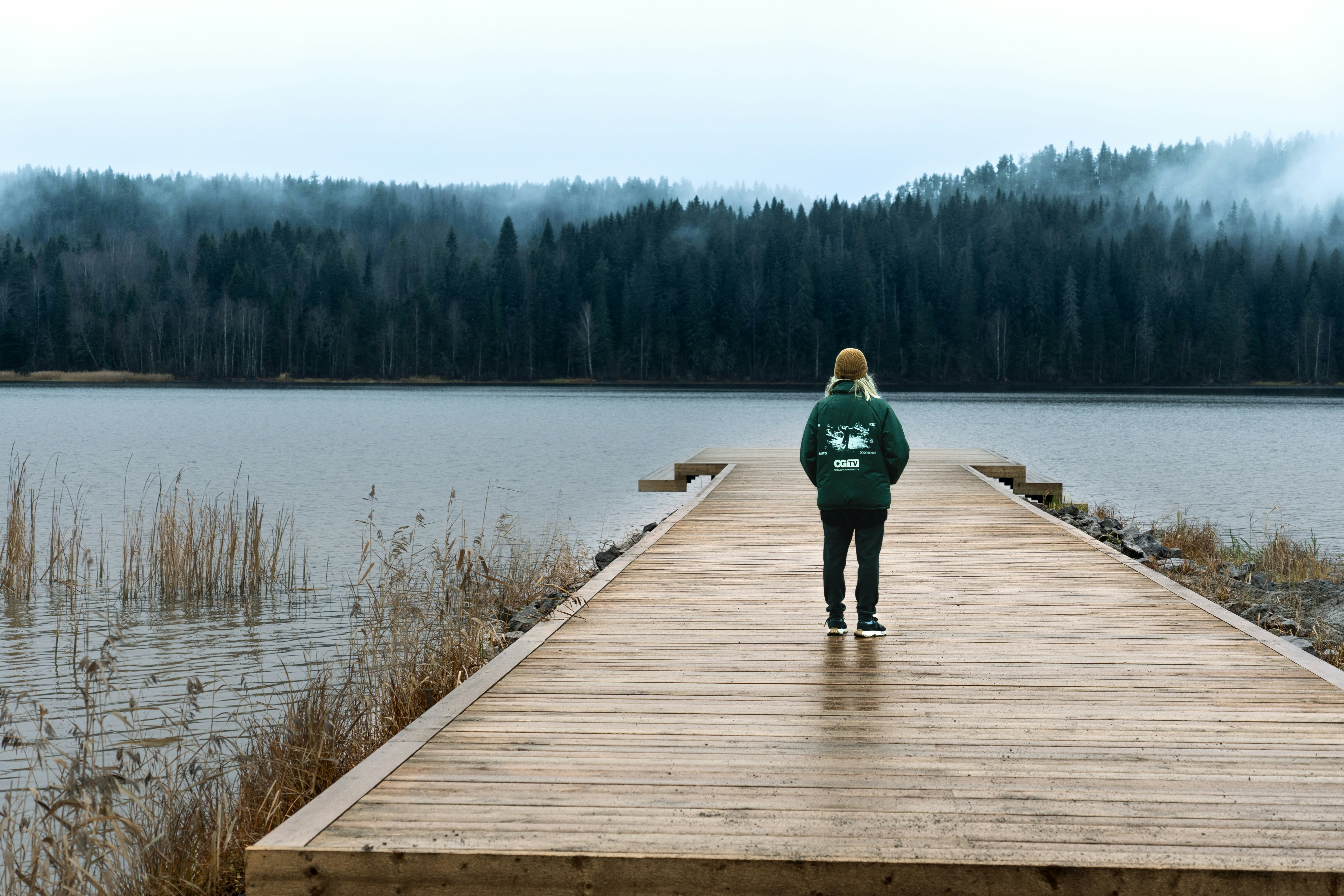 Solitary figure on a misty dock overlooking a fog-blanketed lake