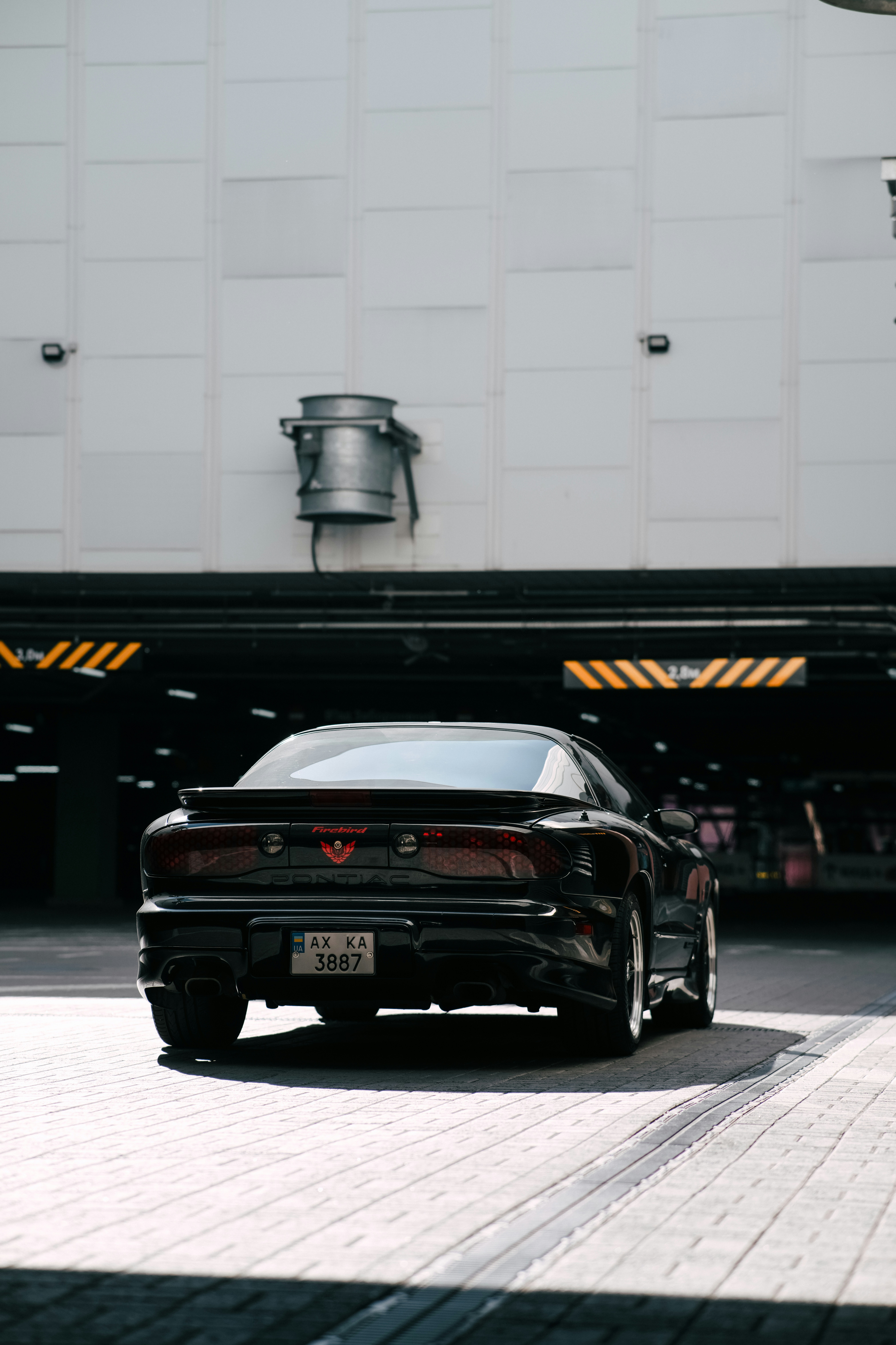 Backed by a Concrete Wall: A Black Muscle Car in Industrial Light
