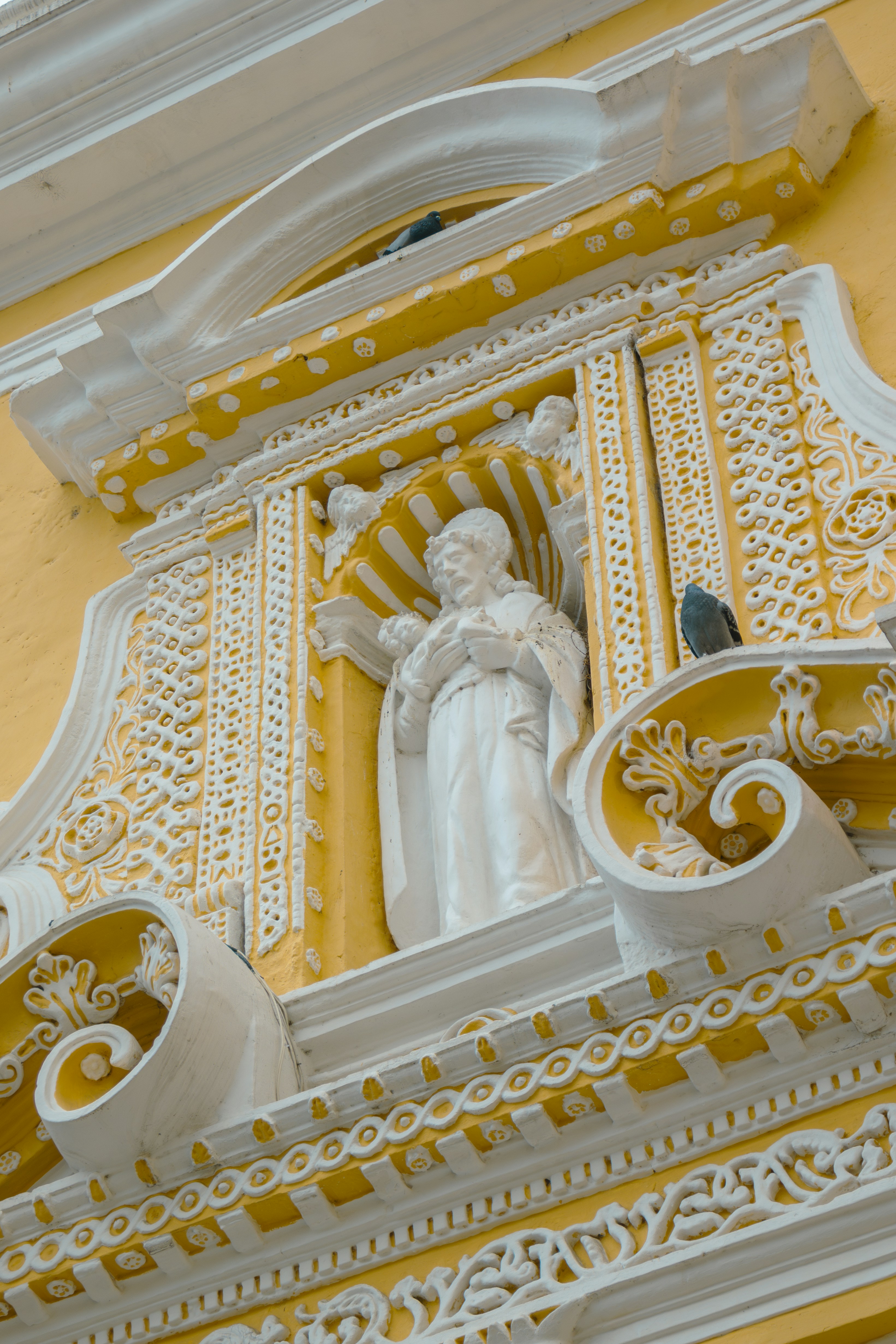 Saint in Sunlit Yellow Lacework on a Carved Facade