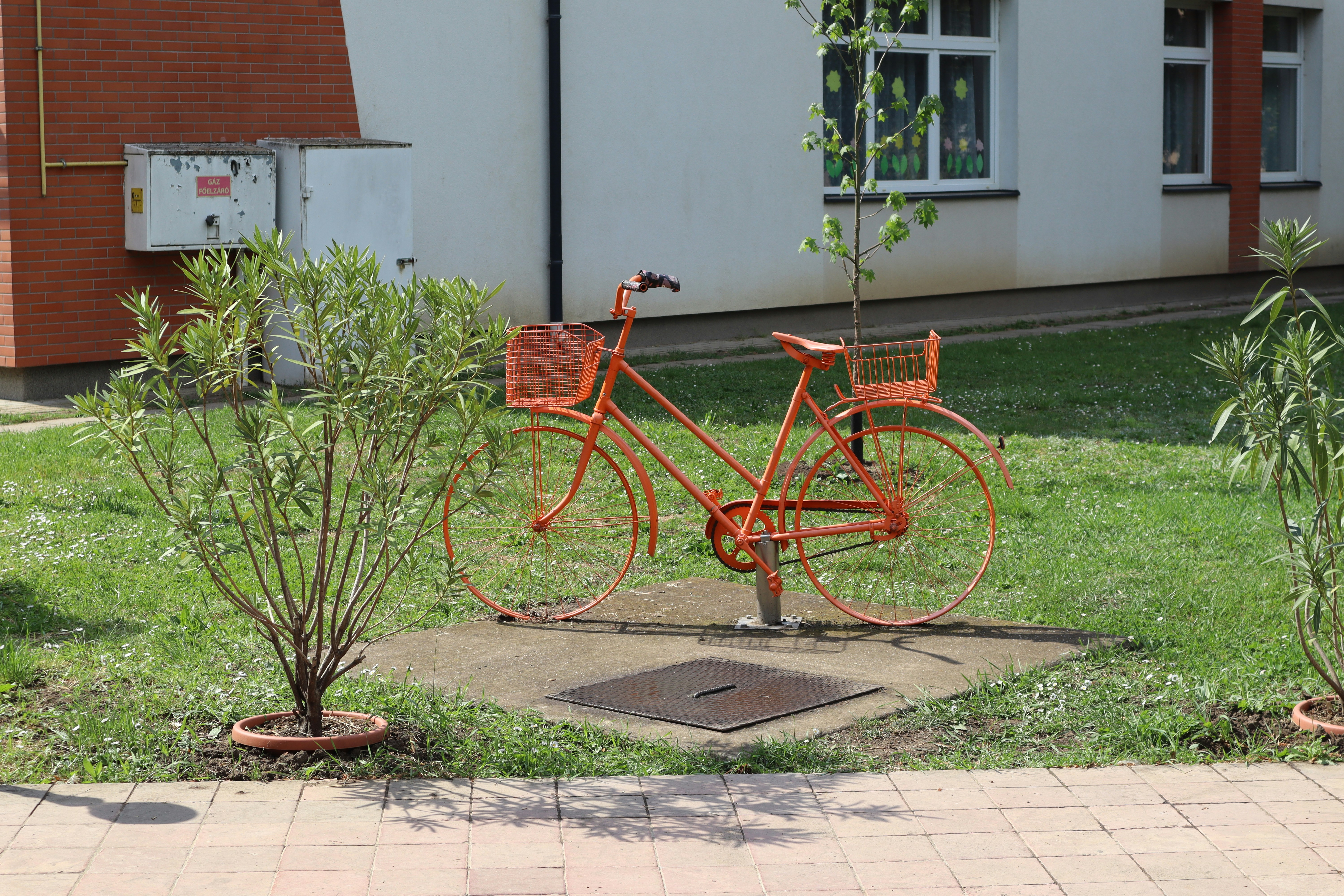 Sunlit Red Bicycle Sculpture in a Quiet Campus Courtyard