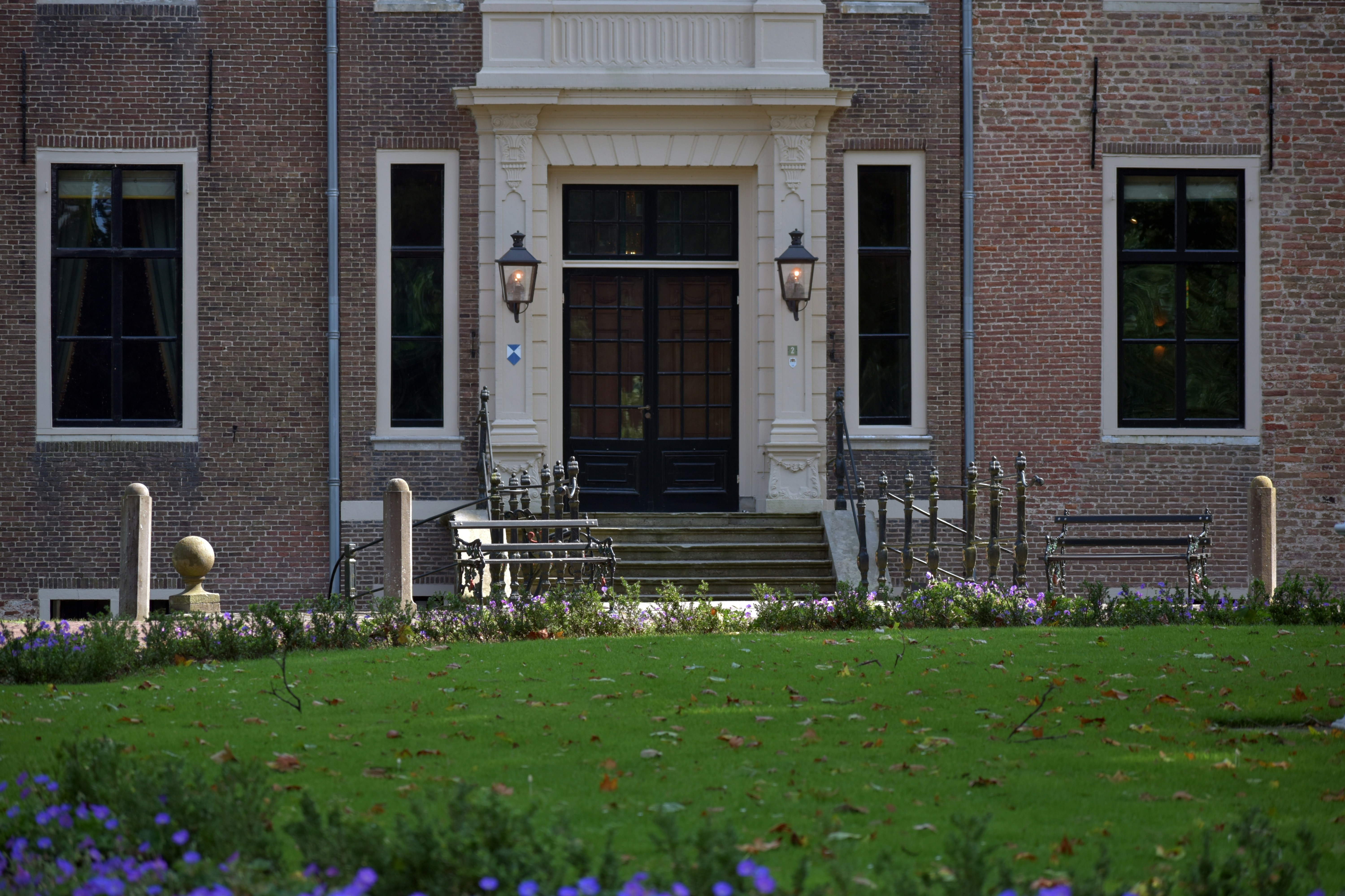 Lantern-Guarded Doorway of a Brick Manor, Surrounded by Spring Blooms