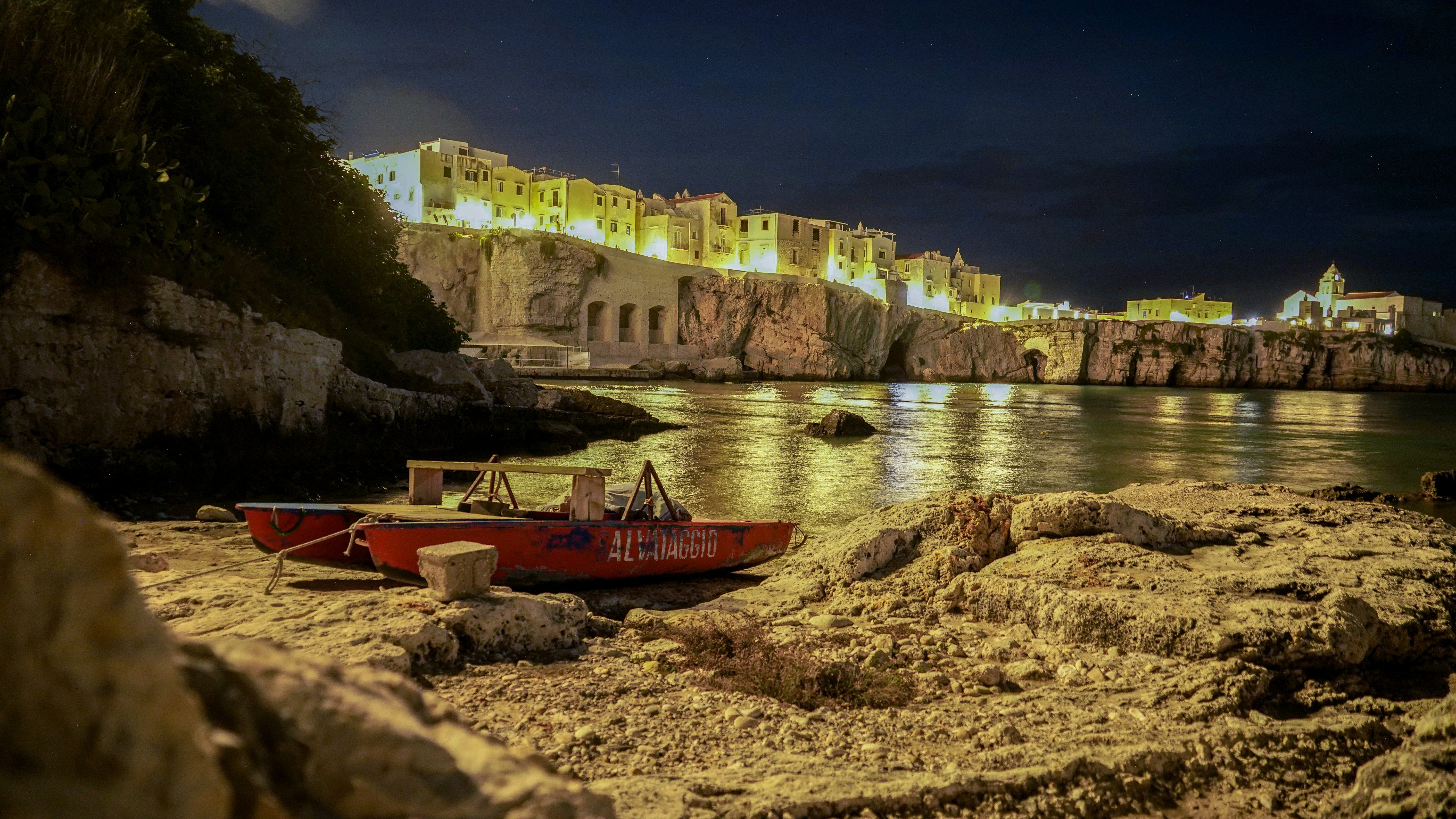 Moonlit Red Boat by a Cliffside Village of Golden Lights