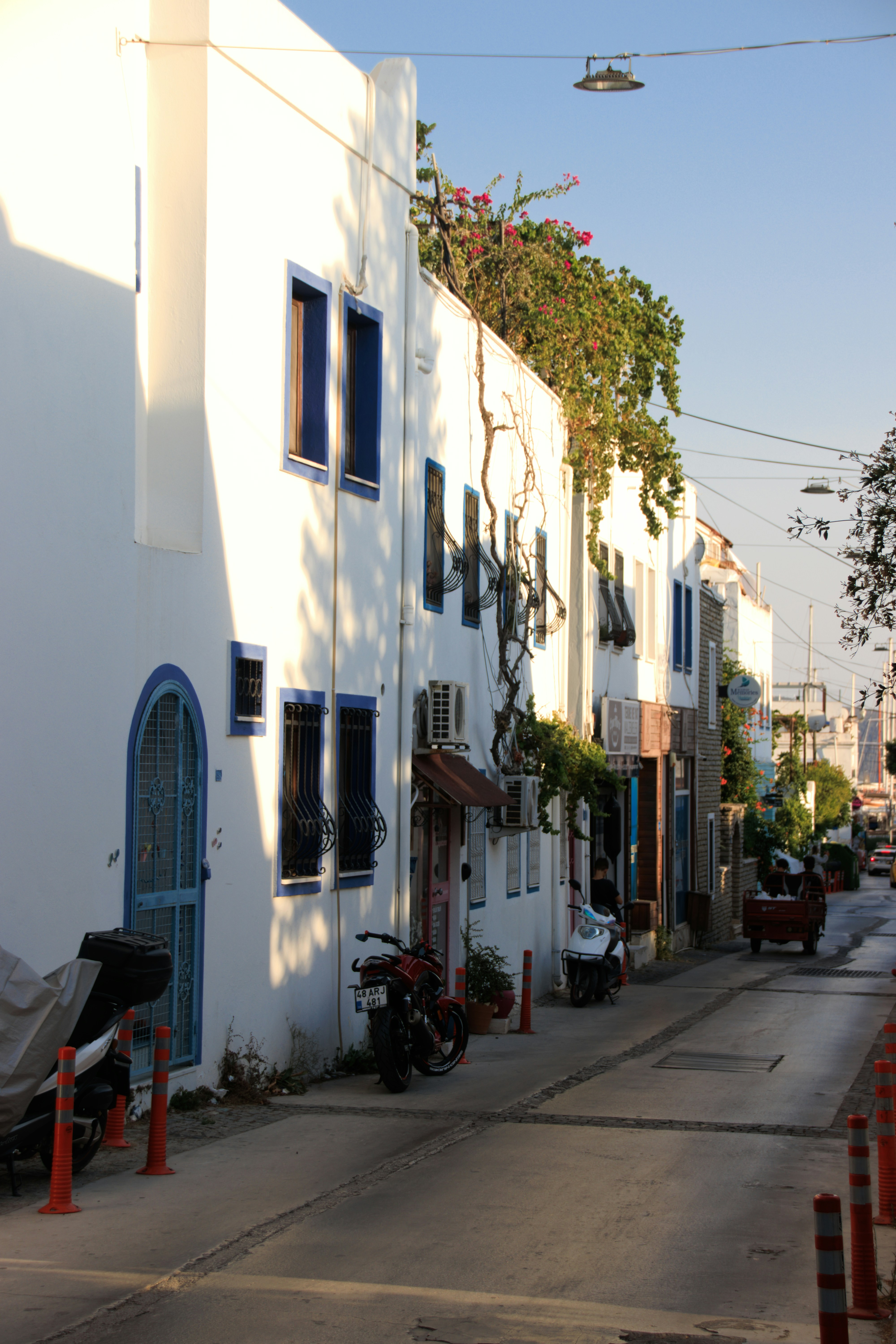 Empty street | A white building with blue windows and a motorcycle parked on the side of the street