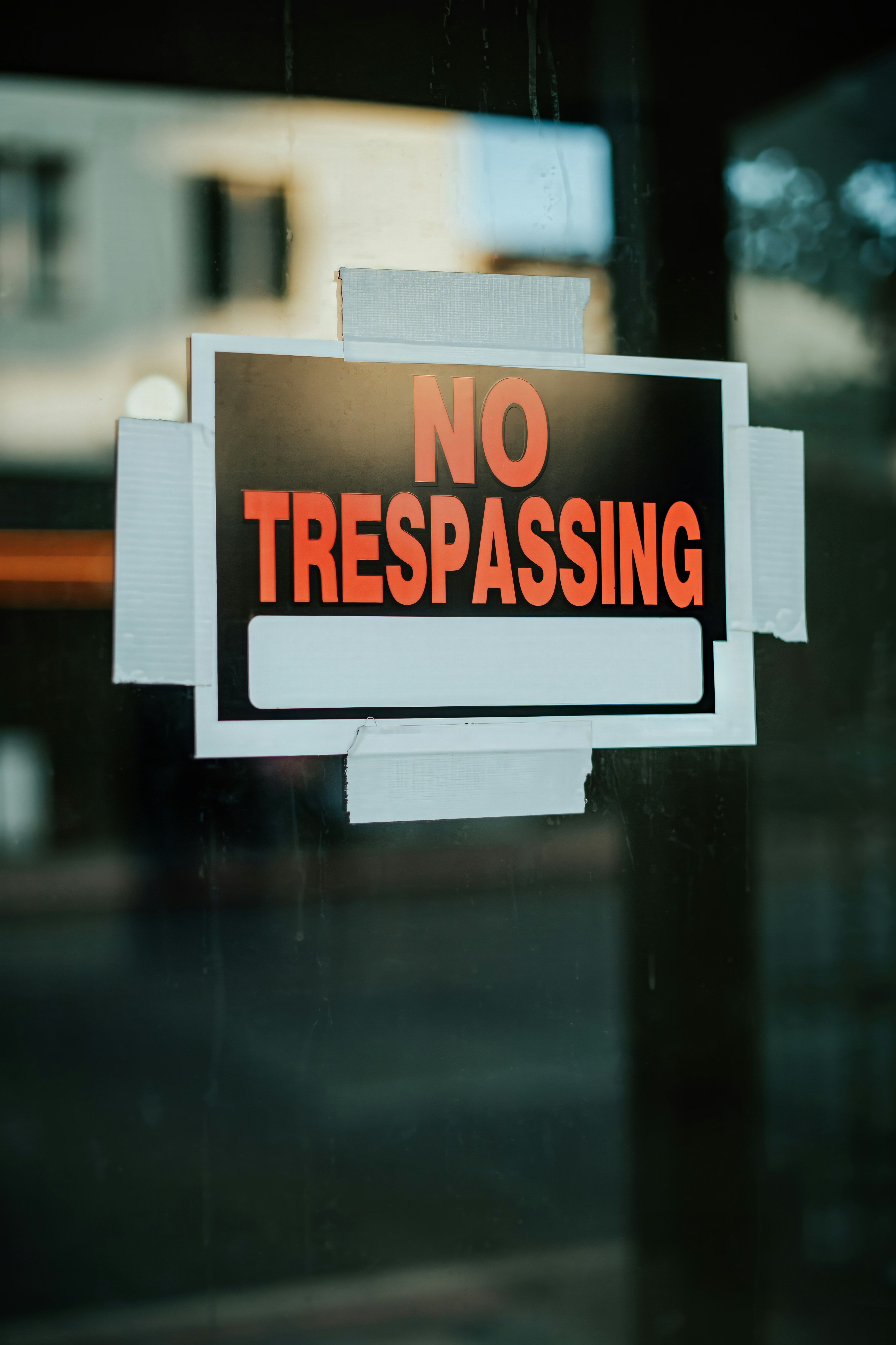 Tape-Bound NO TRESPASSING Sign Clipped to a Glass Door