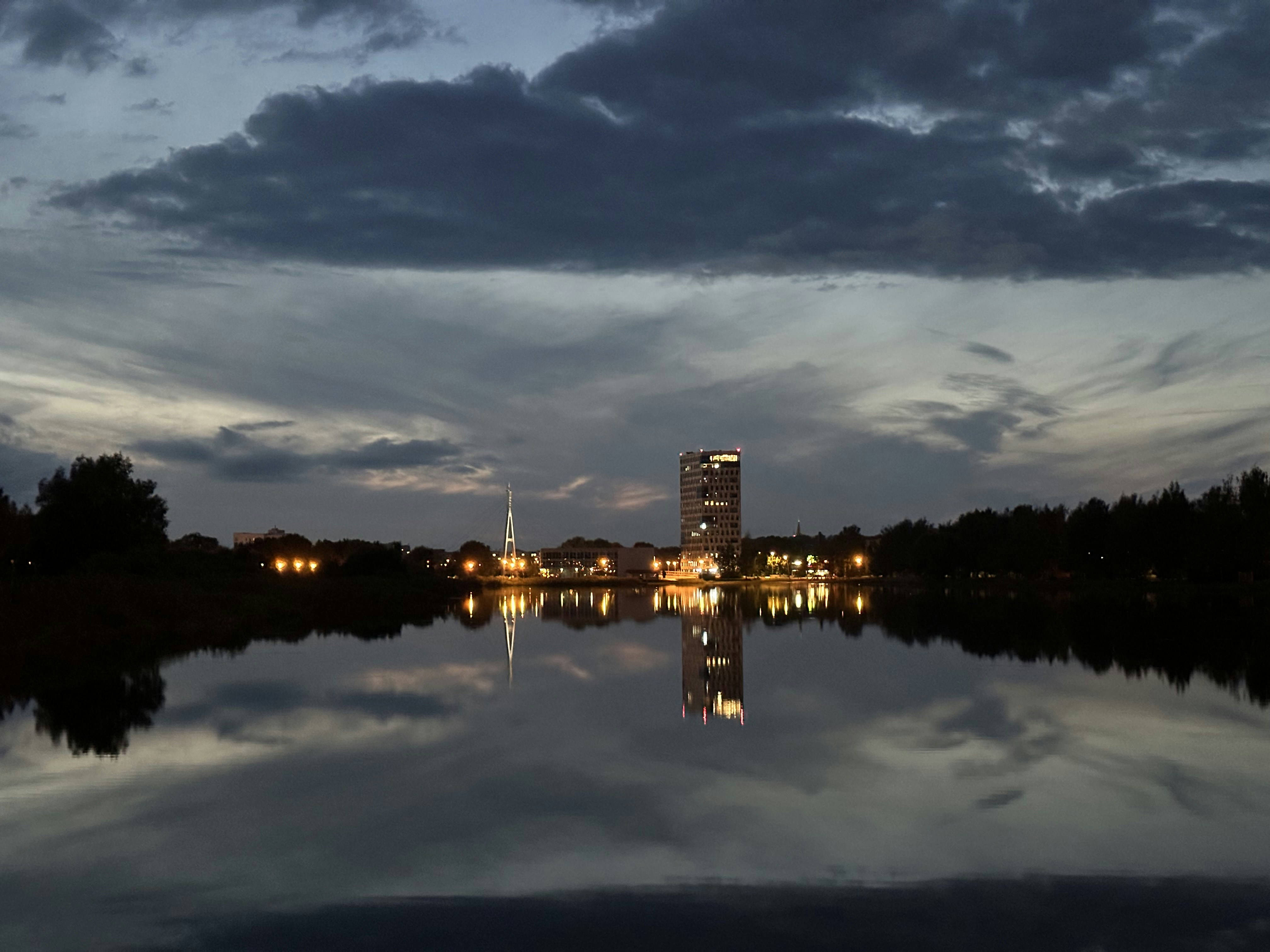 Twin City Lights Reflected: A Serene Riverbank at Dusk