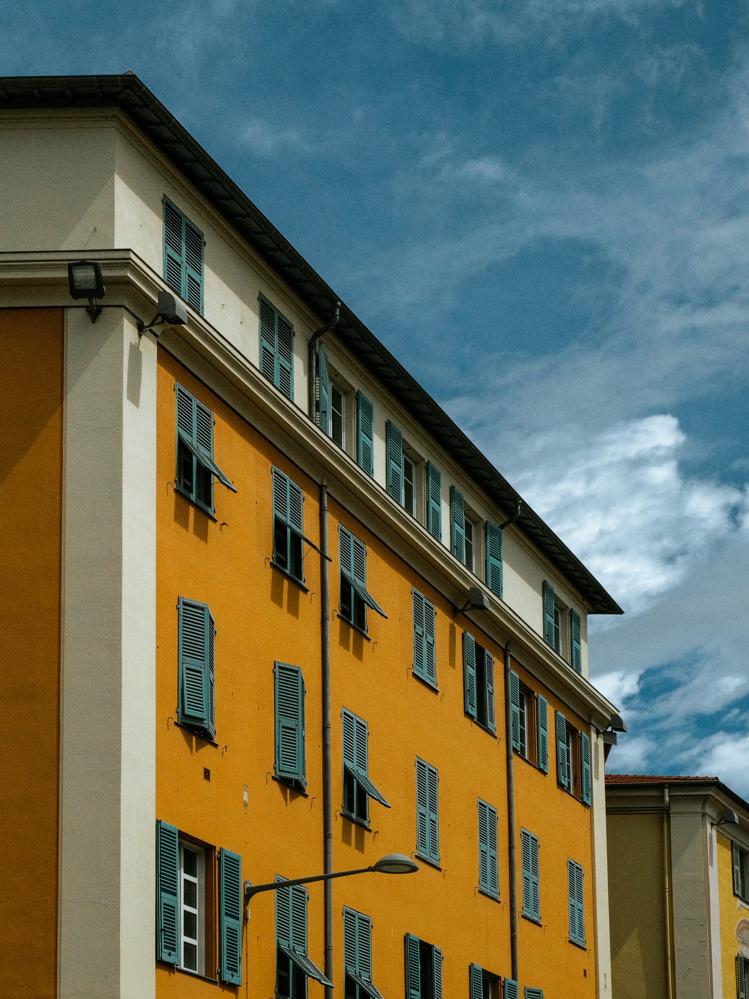 A tall yellow building sitting next to a traffic light photo – Free ...