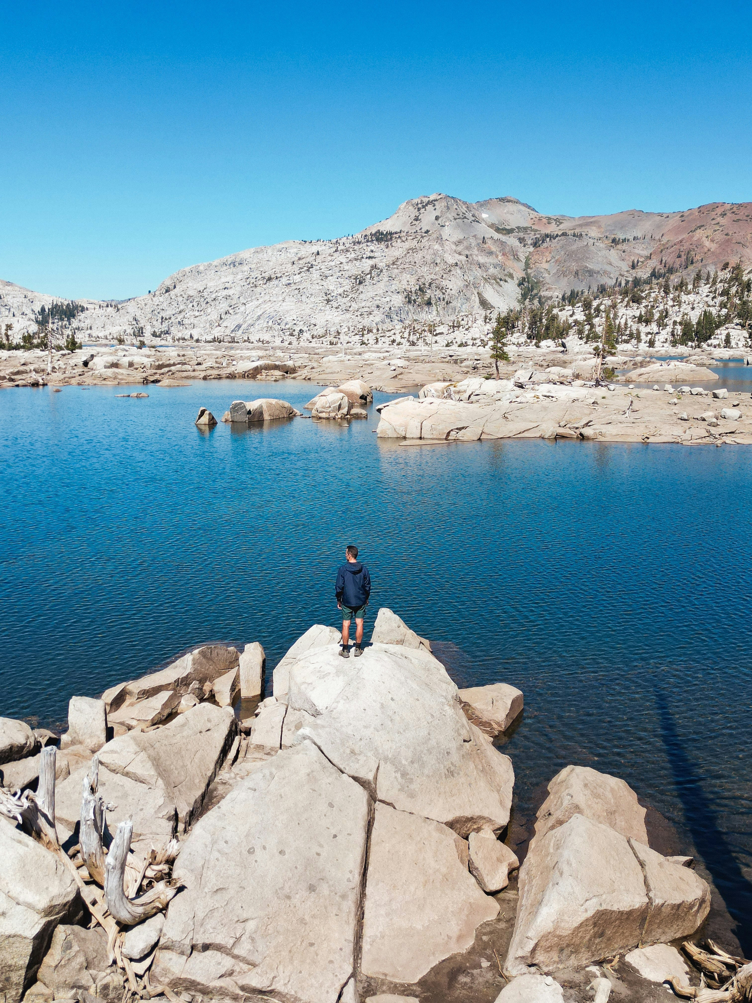 Un homme debout au sommet d’un grand rocher à côté d’un lac photo ...