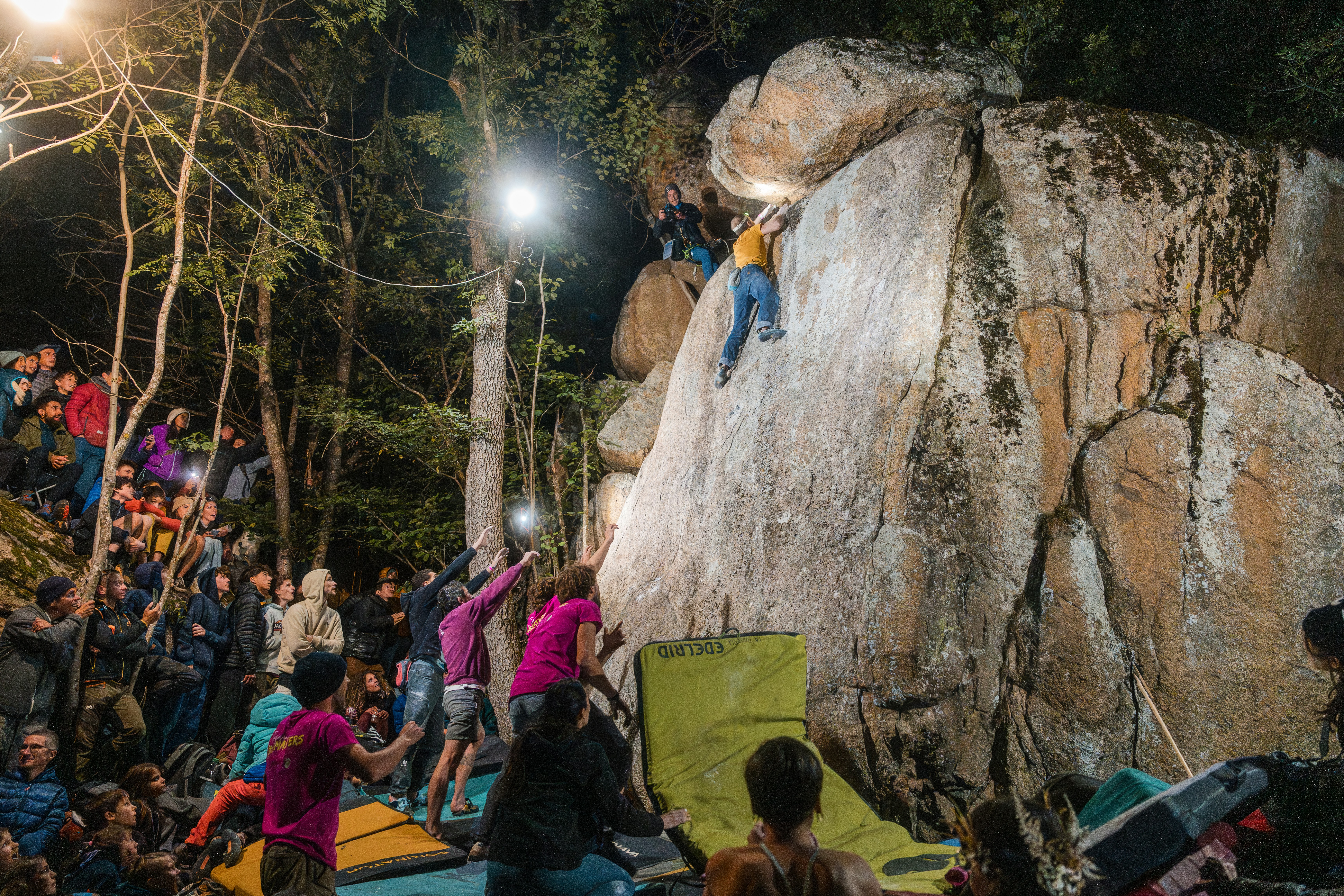 Night Ascent on Granite: A Climber Holds a Bold Grip as a Sea of Spectators Watches