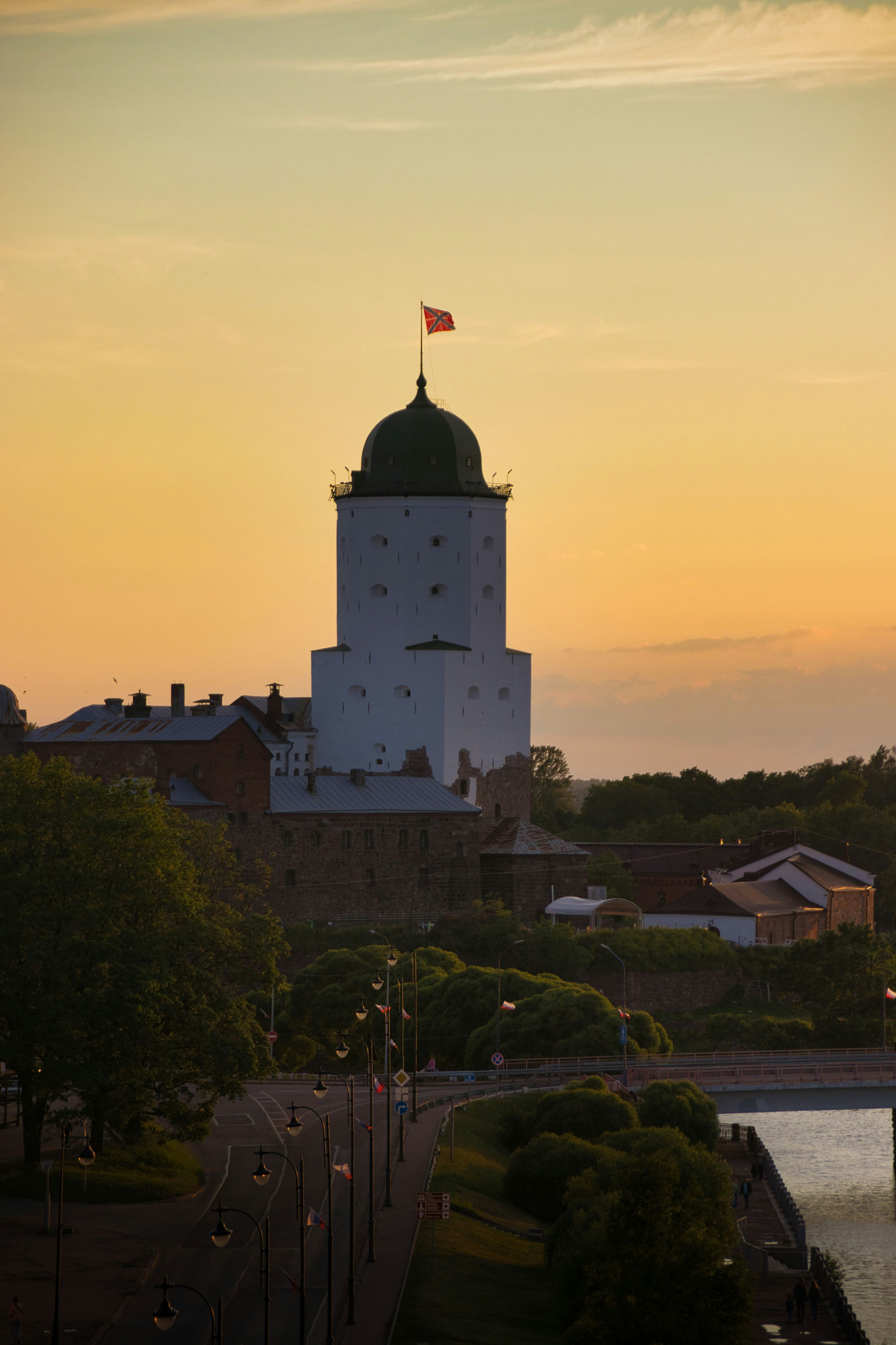 Twilight Fortress: The White Tower with a Green Dome Standing Over a Quiet Riverside Promenade