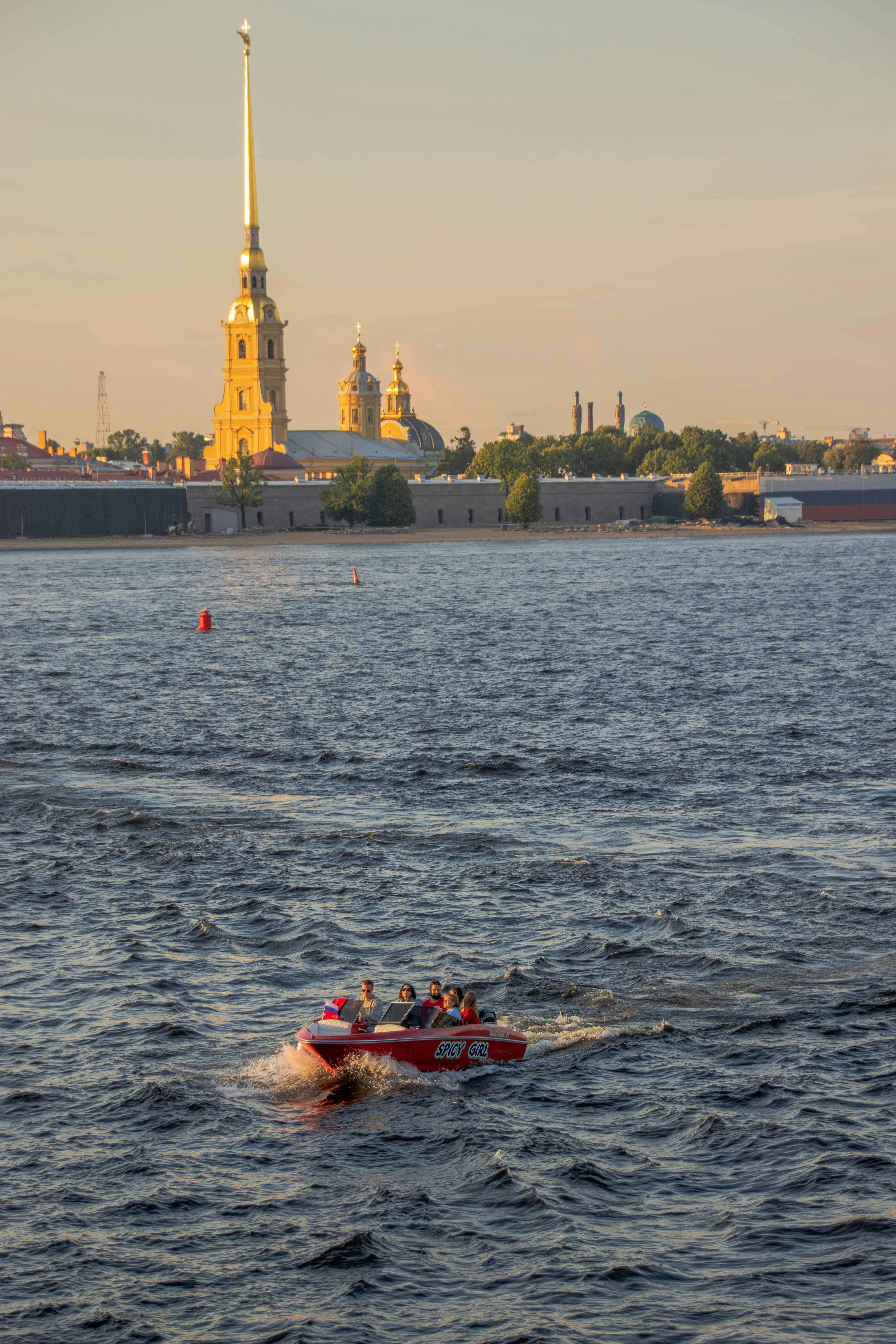 Sunset Wake by the Spire: A Red Boat Cutting Through Golden Hour
