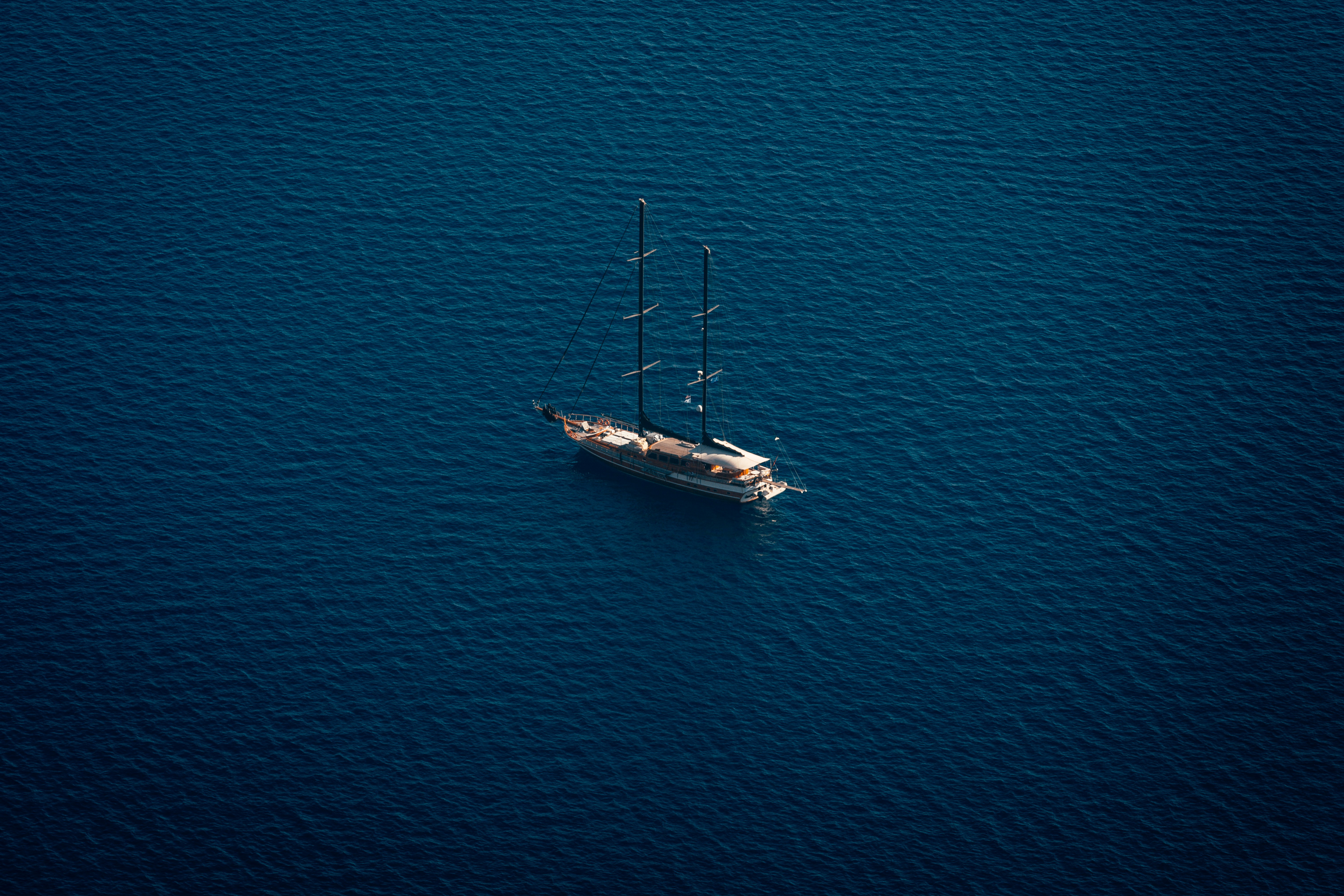 A boat floating in the middle of a body of water photo – Free Santorini ...