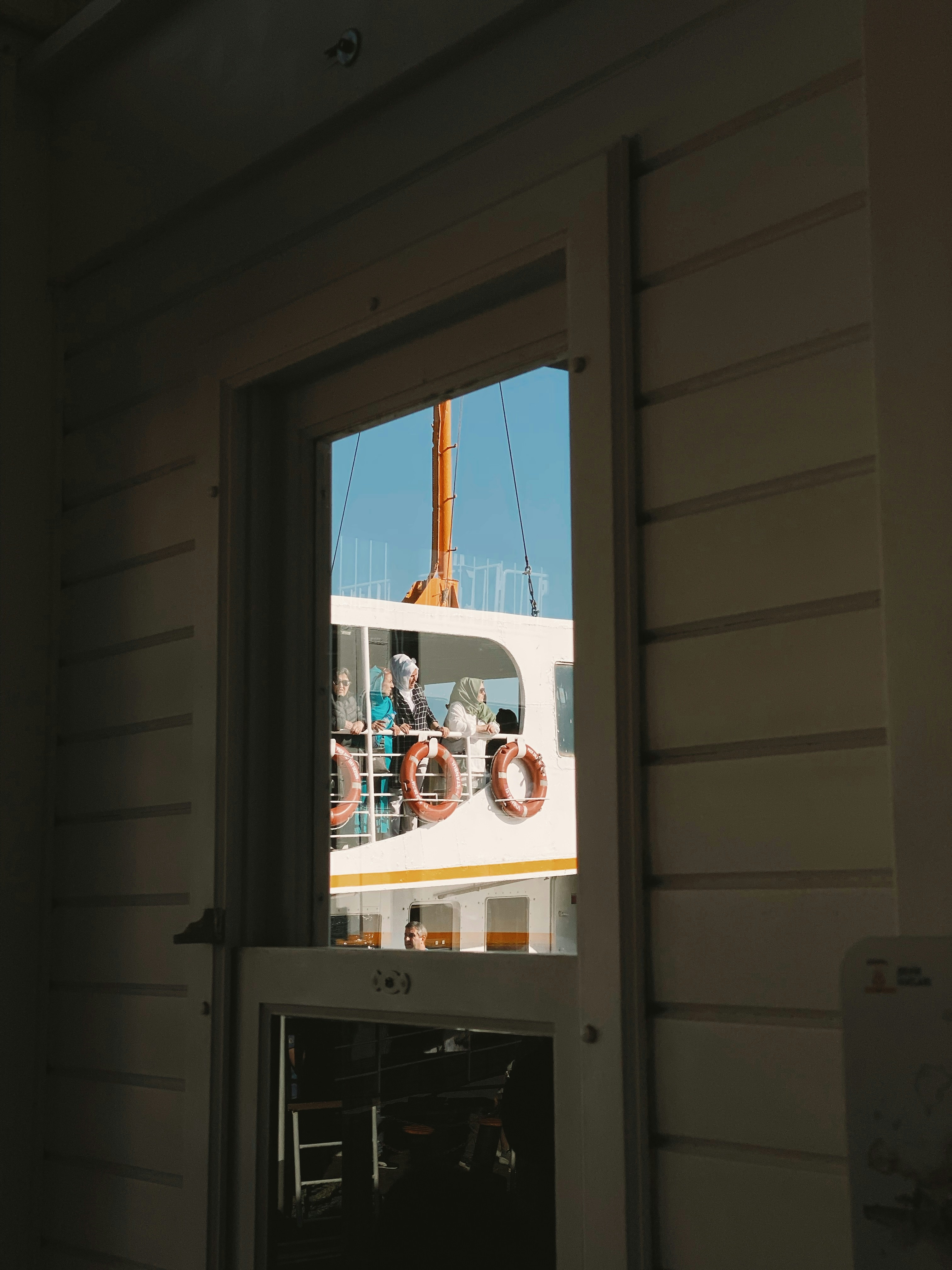 Framed Ferry Life: Passengers and Lifebuoys on a Sunlit Deck