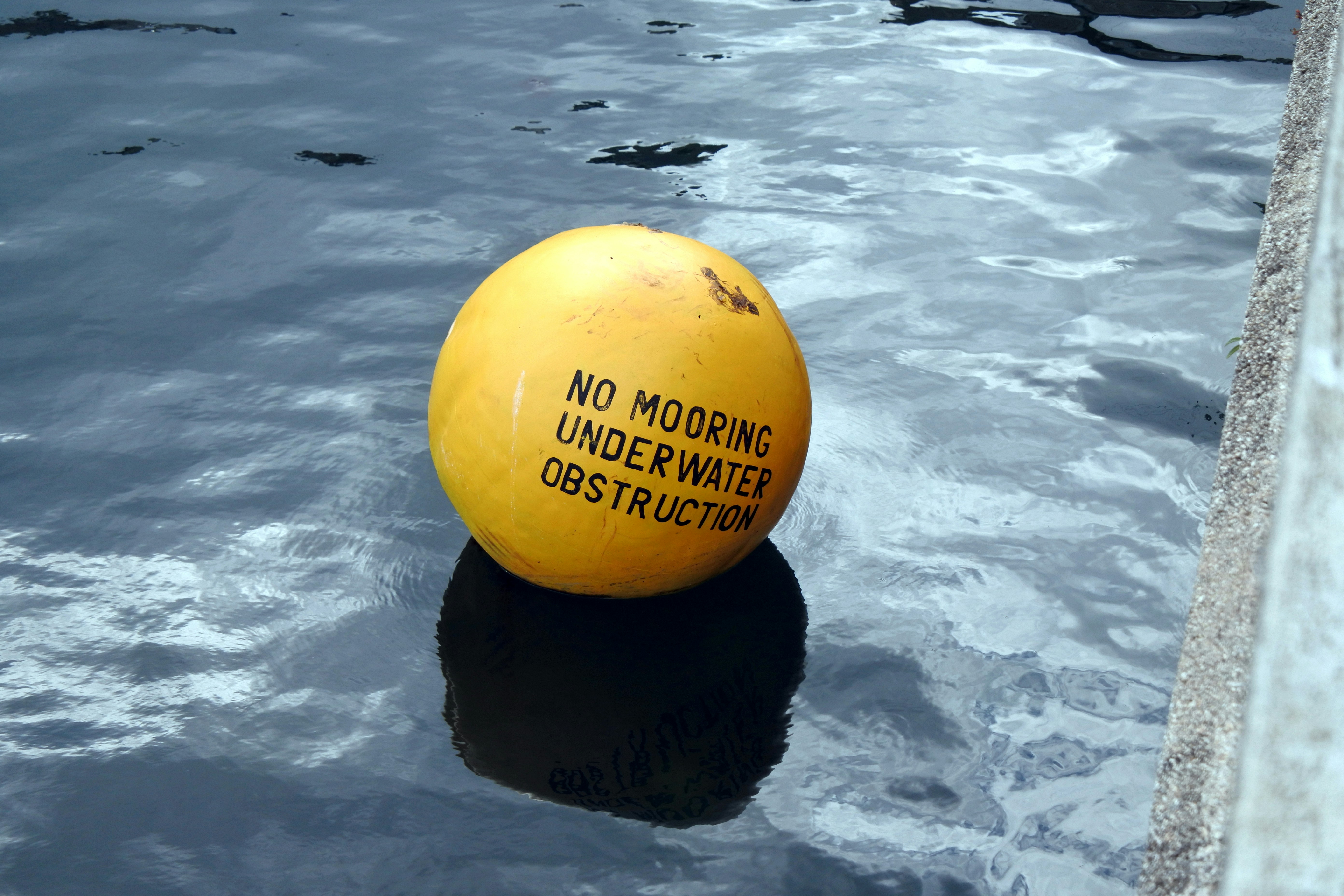 Yellow Buoymark Drifting Along a Pool's Quiet Boundary