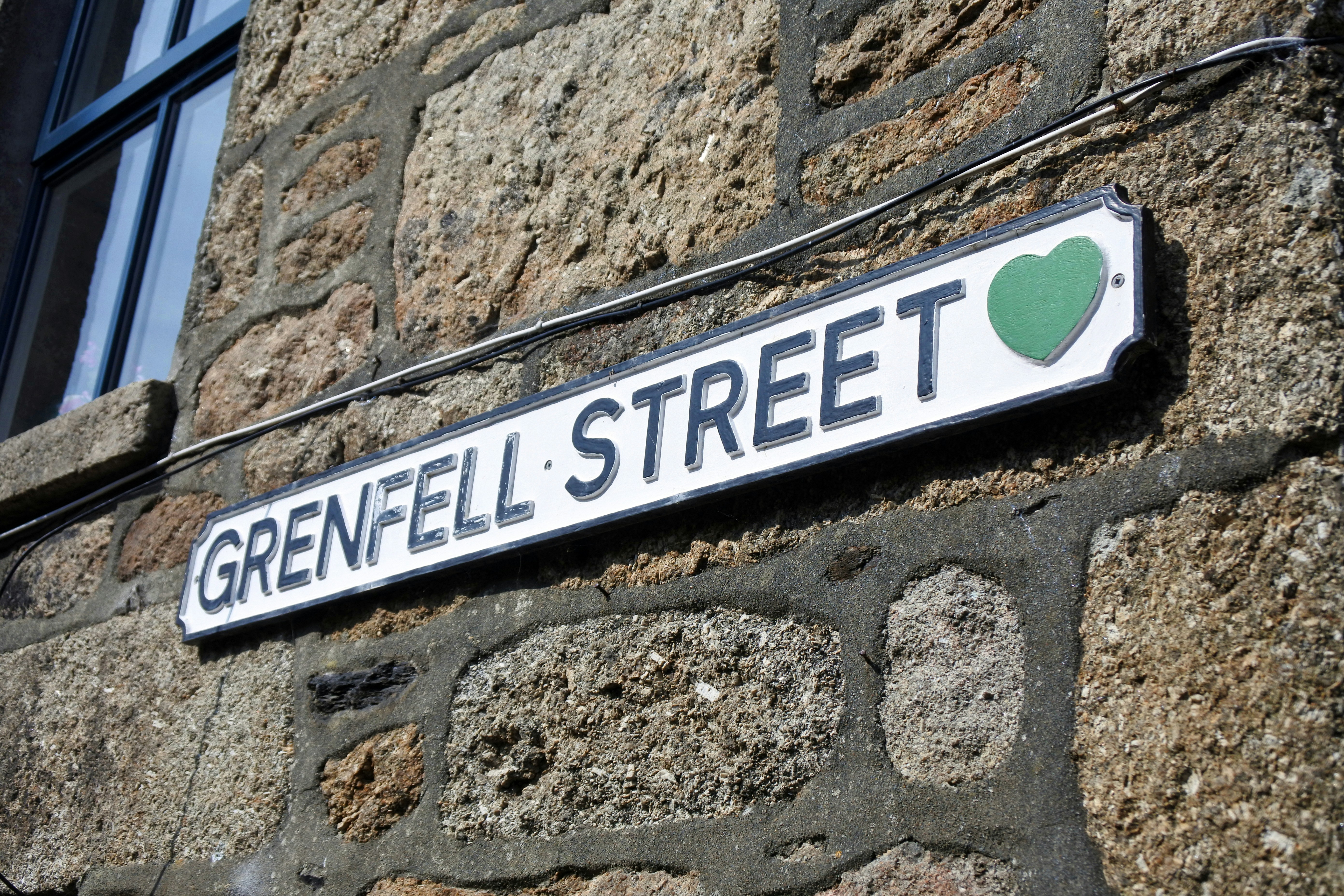 A street sign mounted to the side of a stone building photo – Free ...