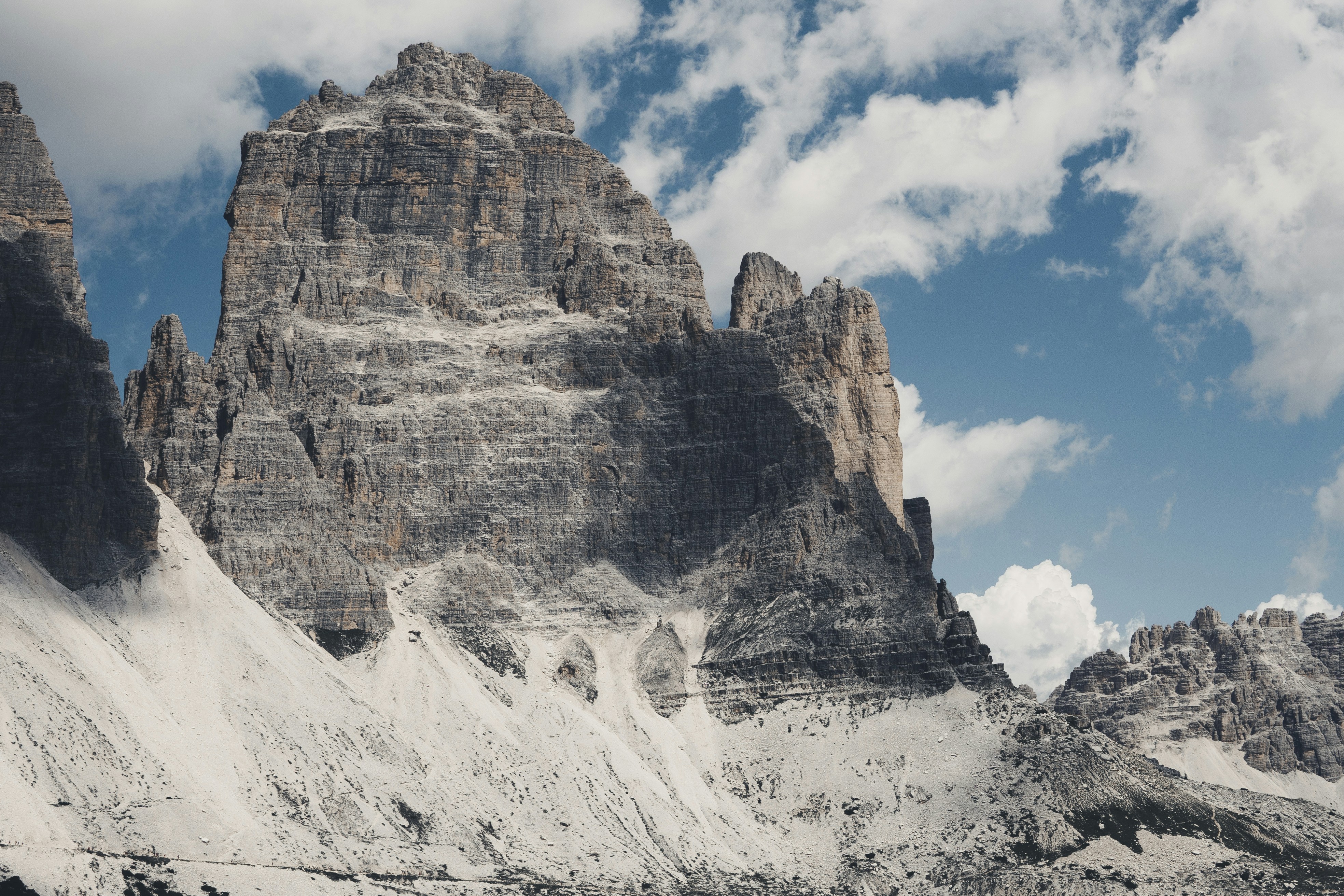 Towering rock formations of Tre Cime under a partly cloudy sky.