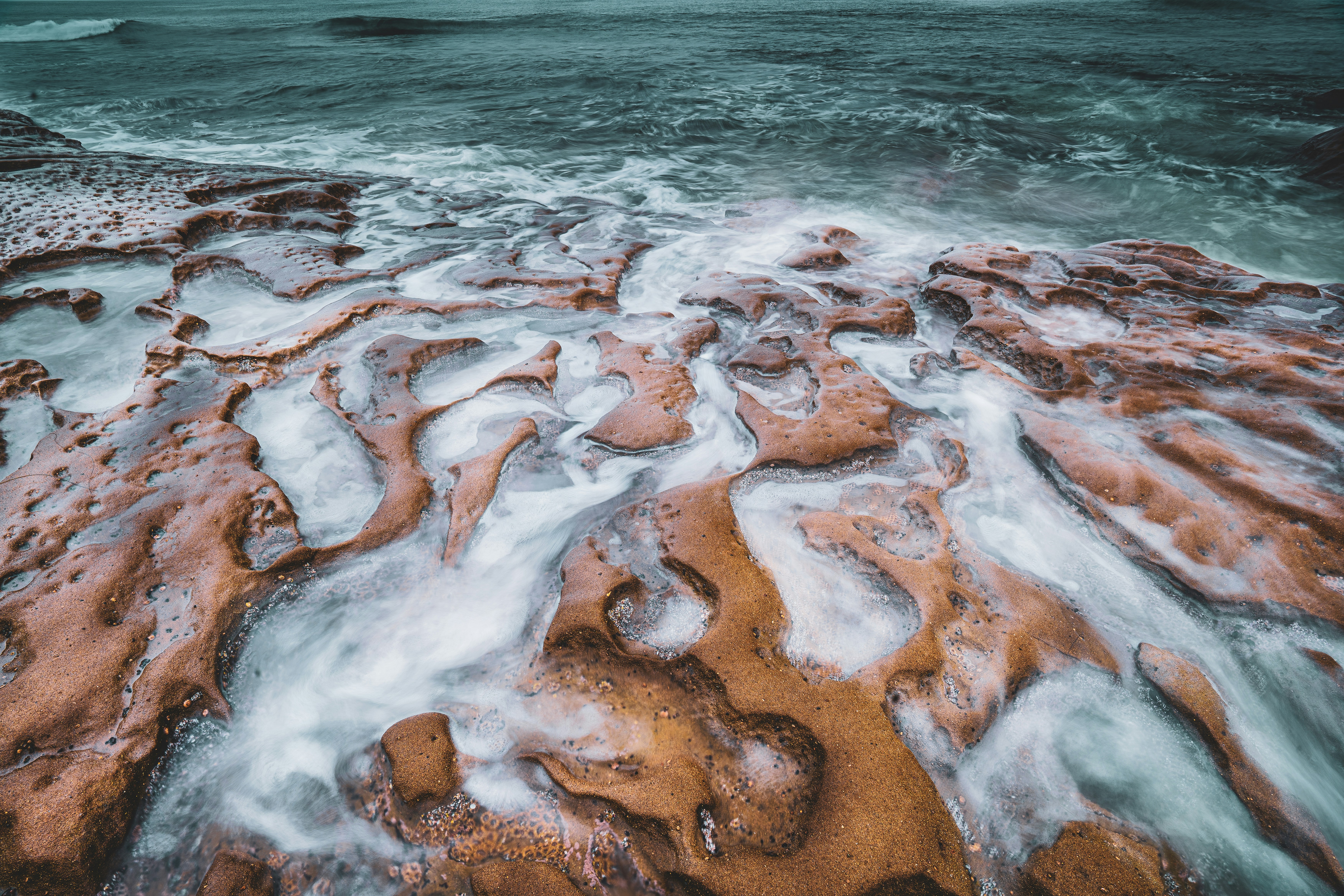 A large body of water surrounded by rocks photo – Free Sea Image on ...