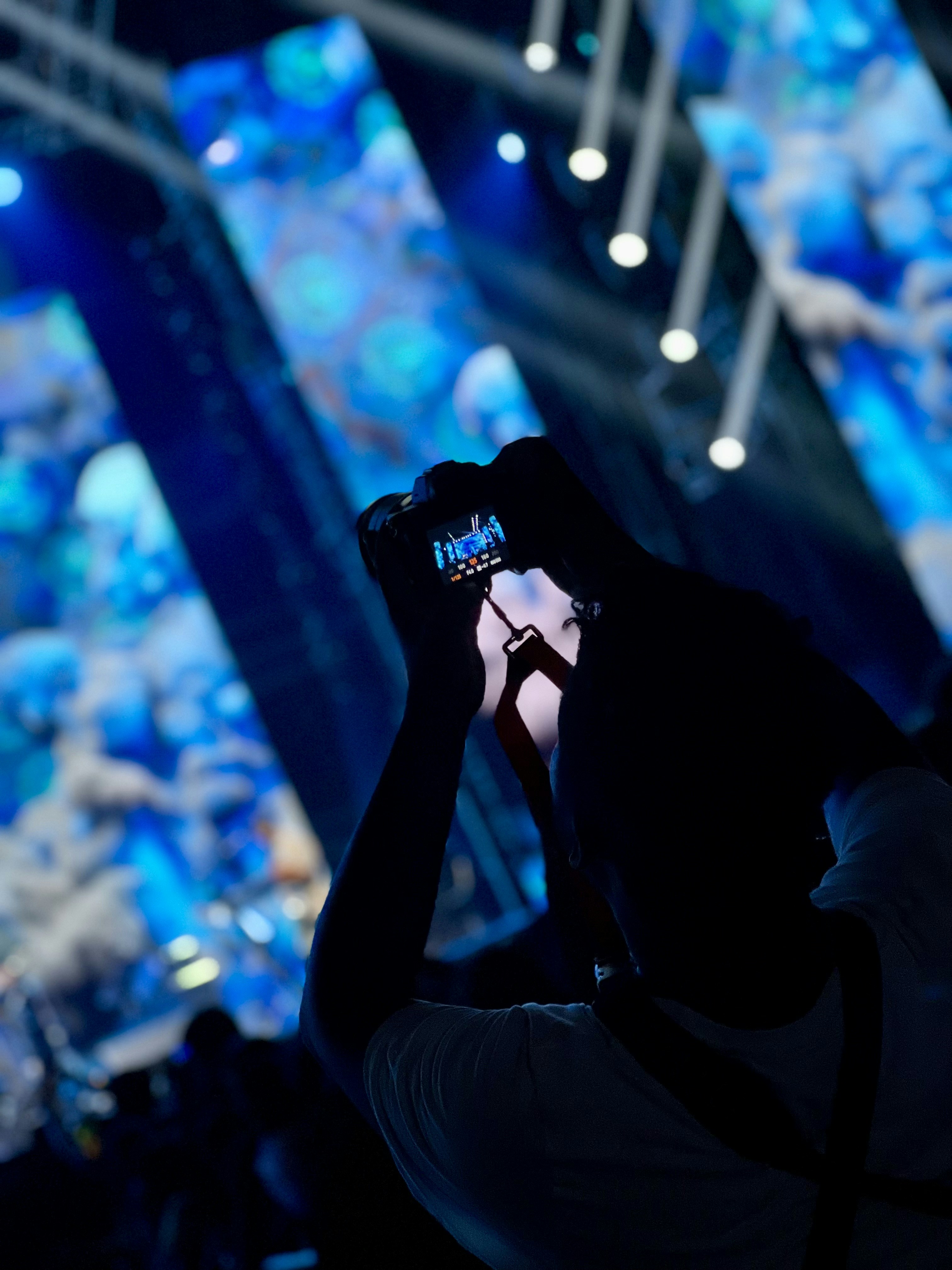 Center-Stage Snap: A Fan Frames a Neon-Blue Concert Night