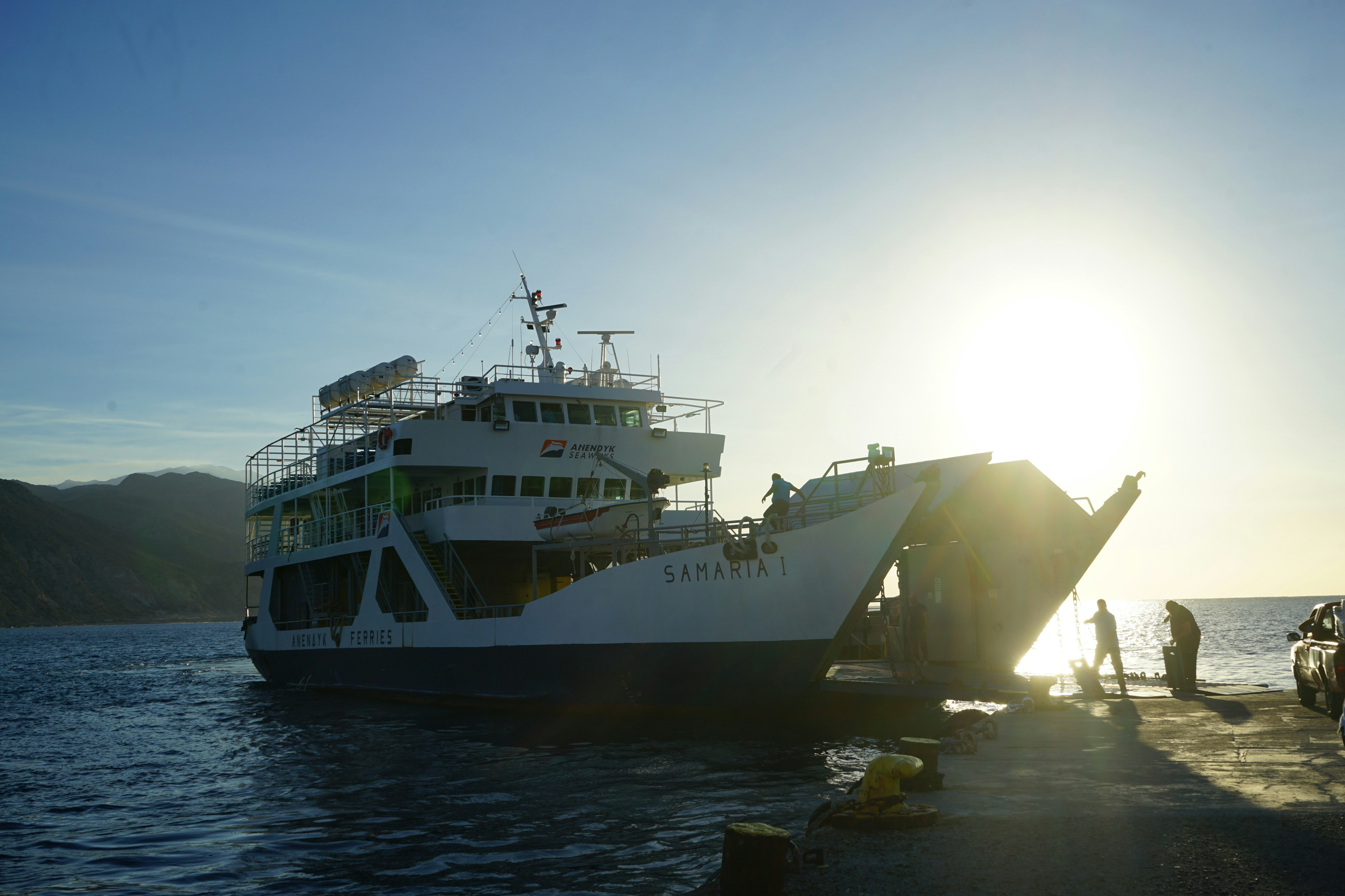 Backlit Ferry at the Pier: Silhouettes and Sunflare over a Quiet Harbor