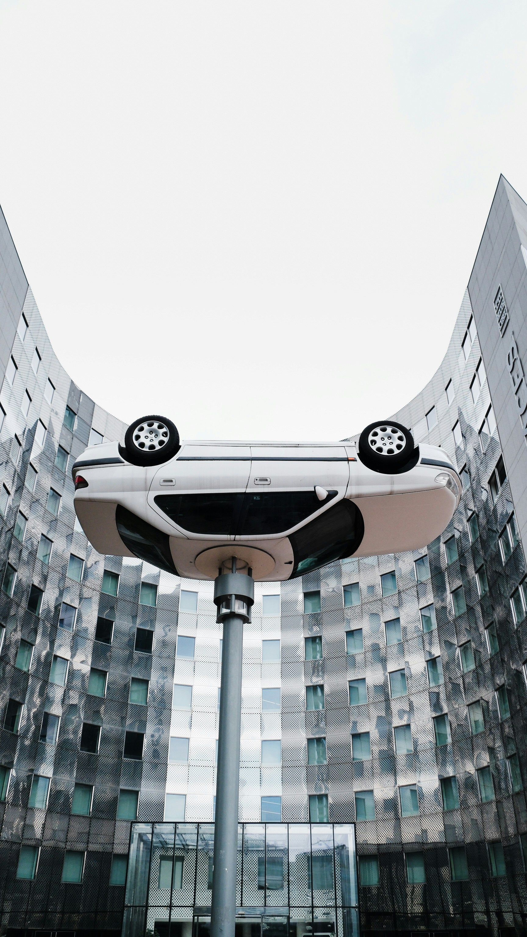 Upside-Down Car Suspended Above a Circular Glass Atrium