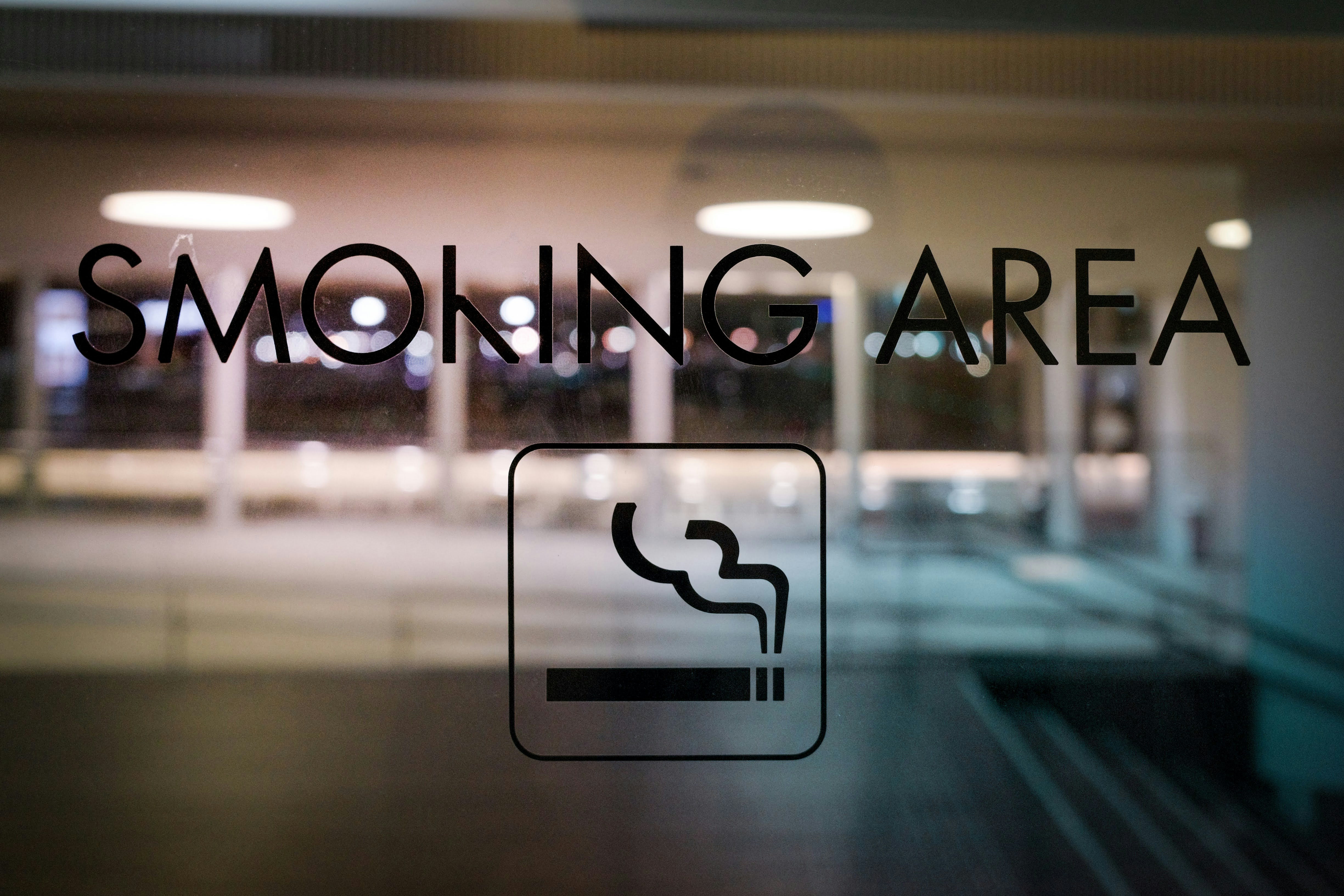 Glass Threshold Signage: Smoking Area with Cigarette Icon in a Dim Corridor