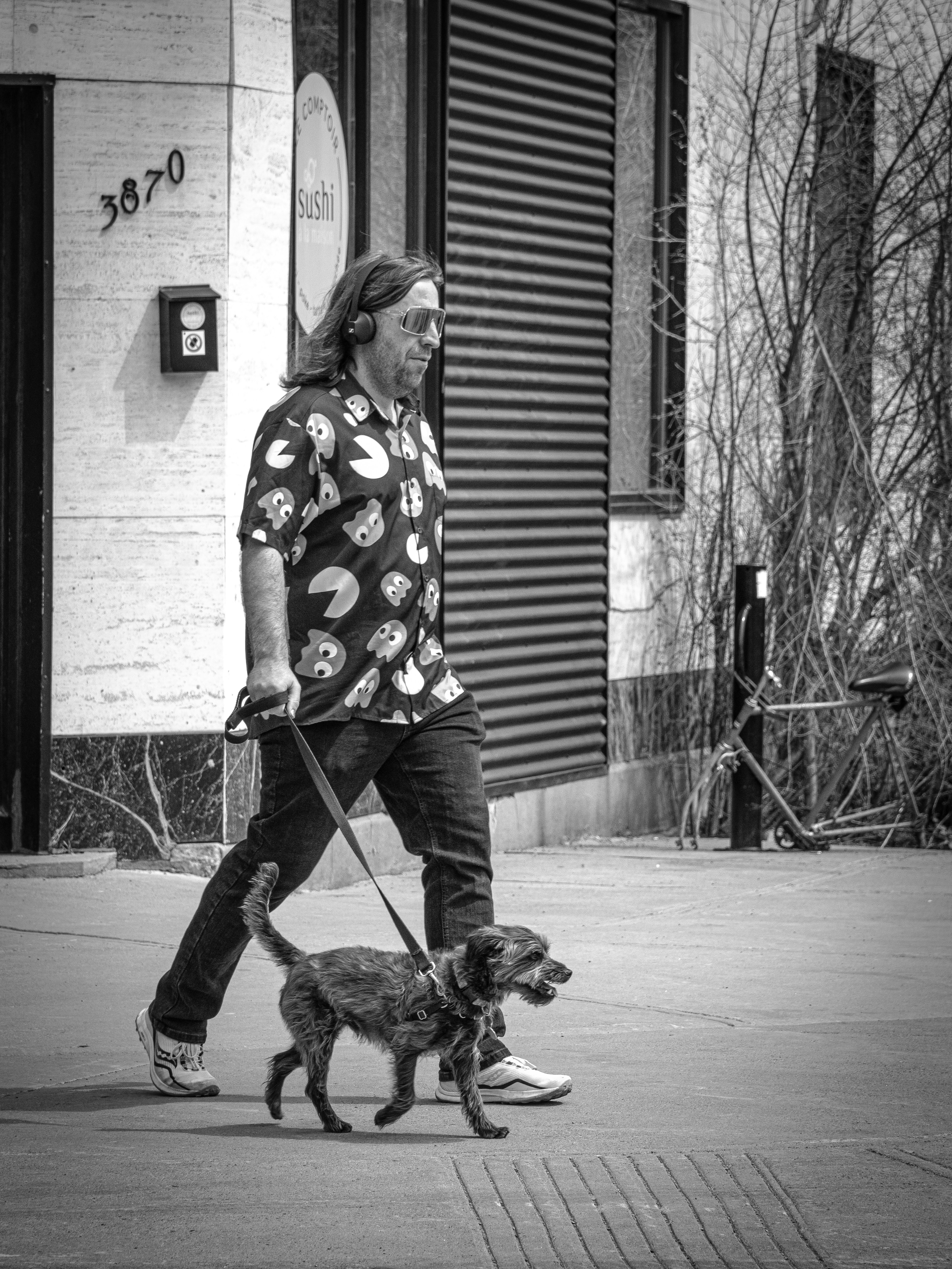 Patterned Stroll: Pac-Man Shirt and a Dog on a Quiet City Walk