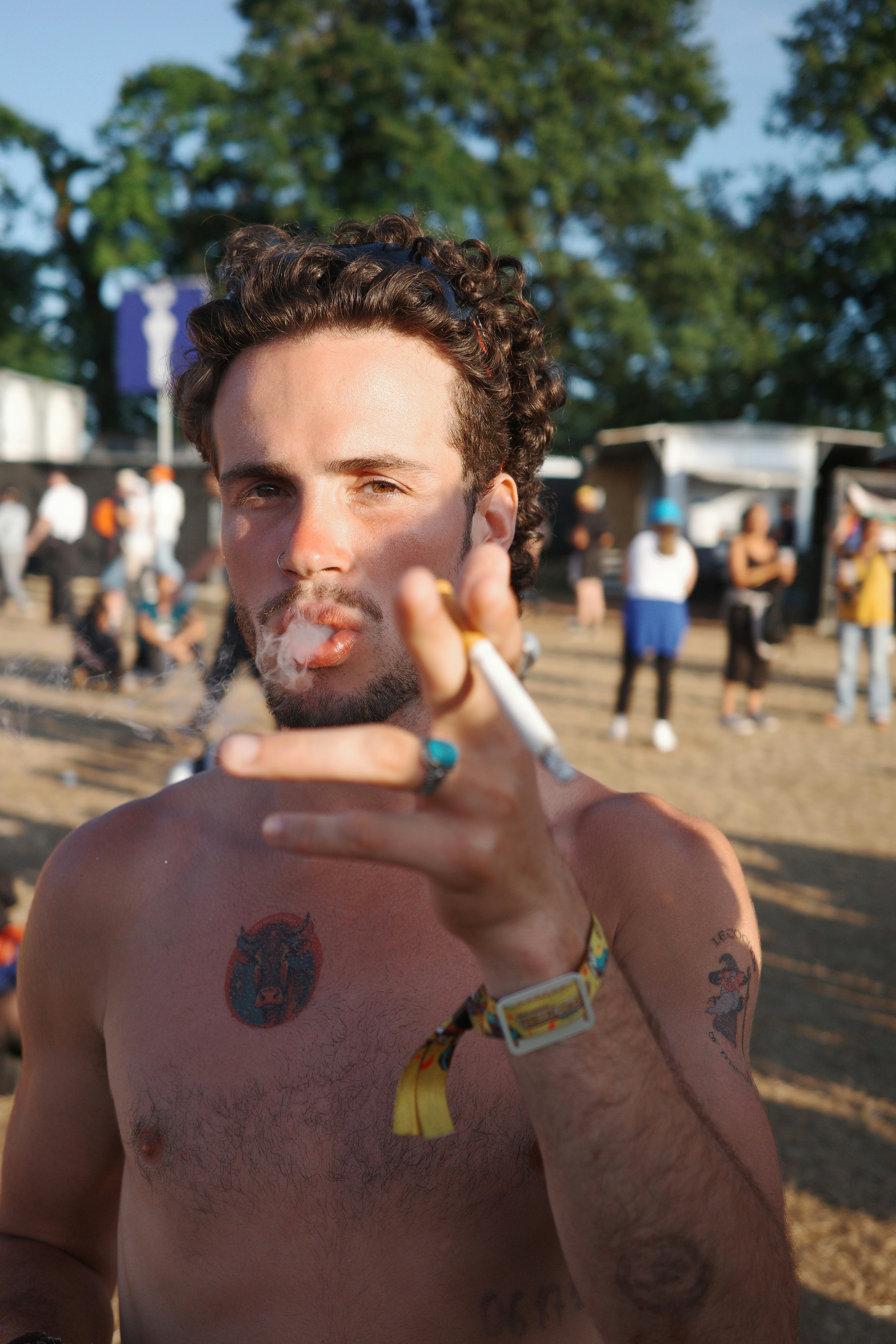 A shirtless man smoking a cigarette at a festival photo – Free Head ...