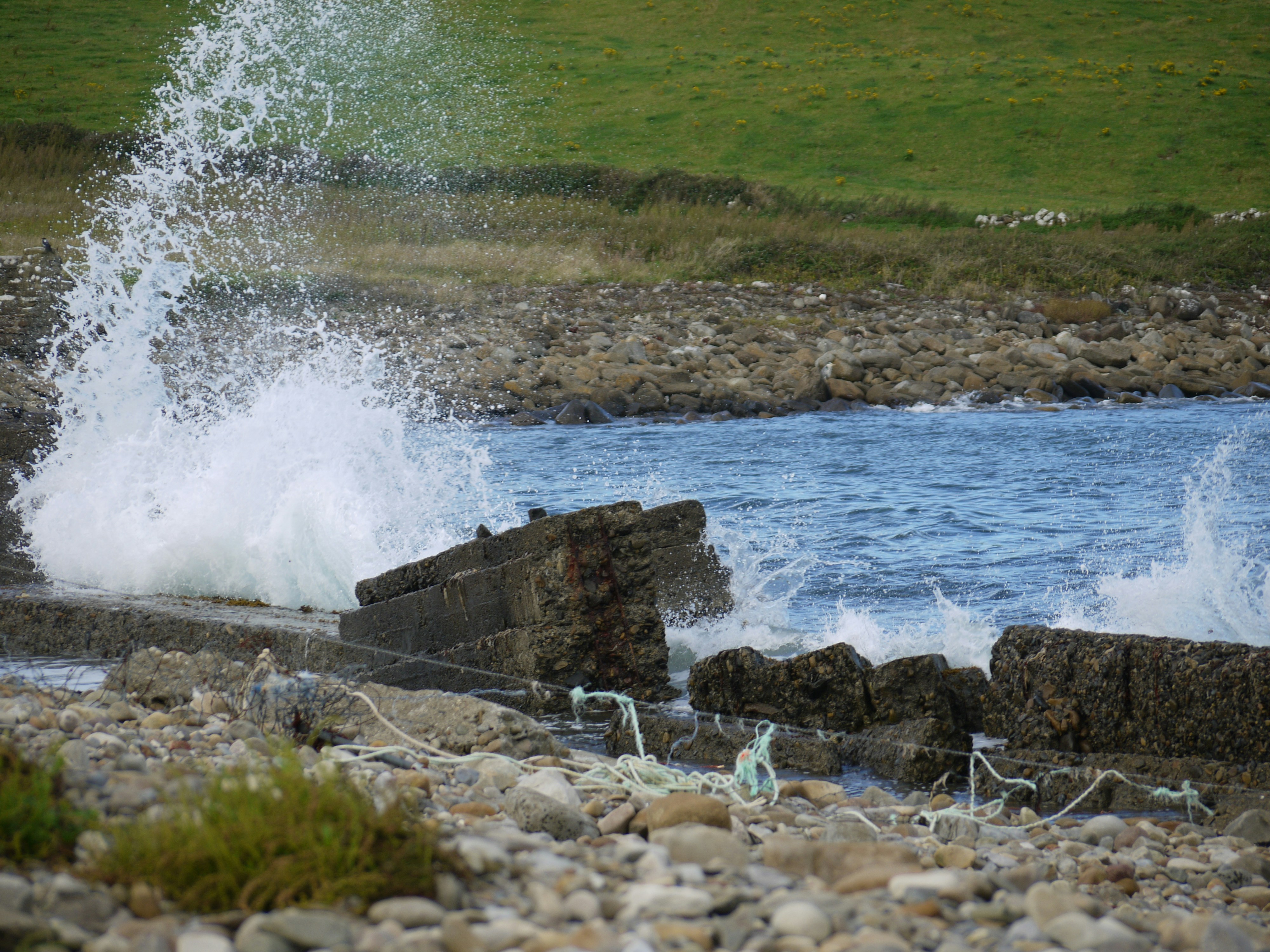 A water spouting out of the rocks near a body of water photo – Free ...
