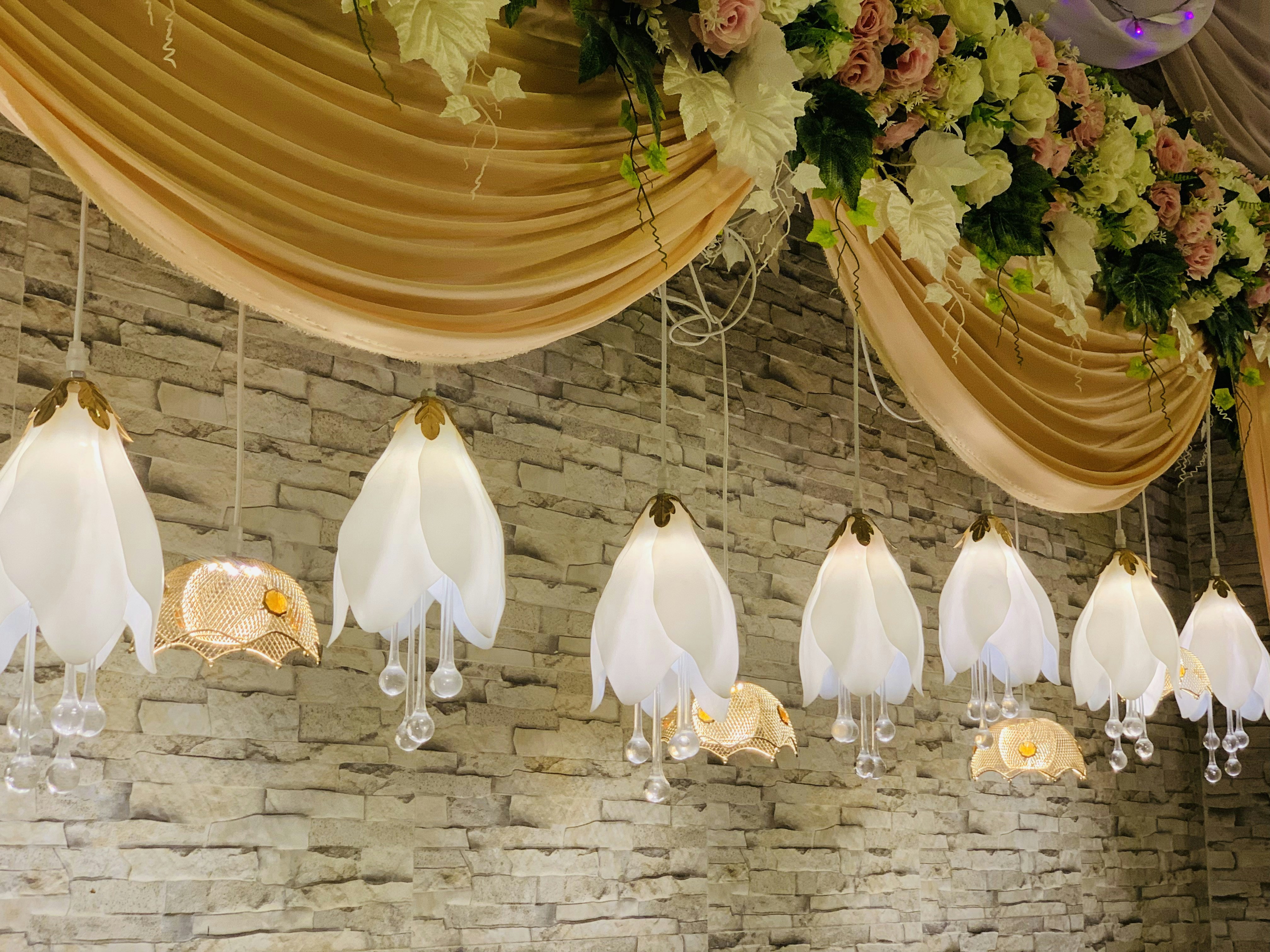 Lantern Chorus Under Golden Drapery: Floral Accents Over a Stone Wall