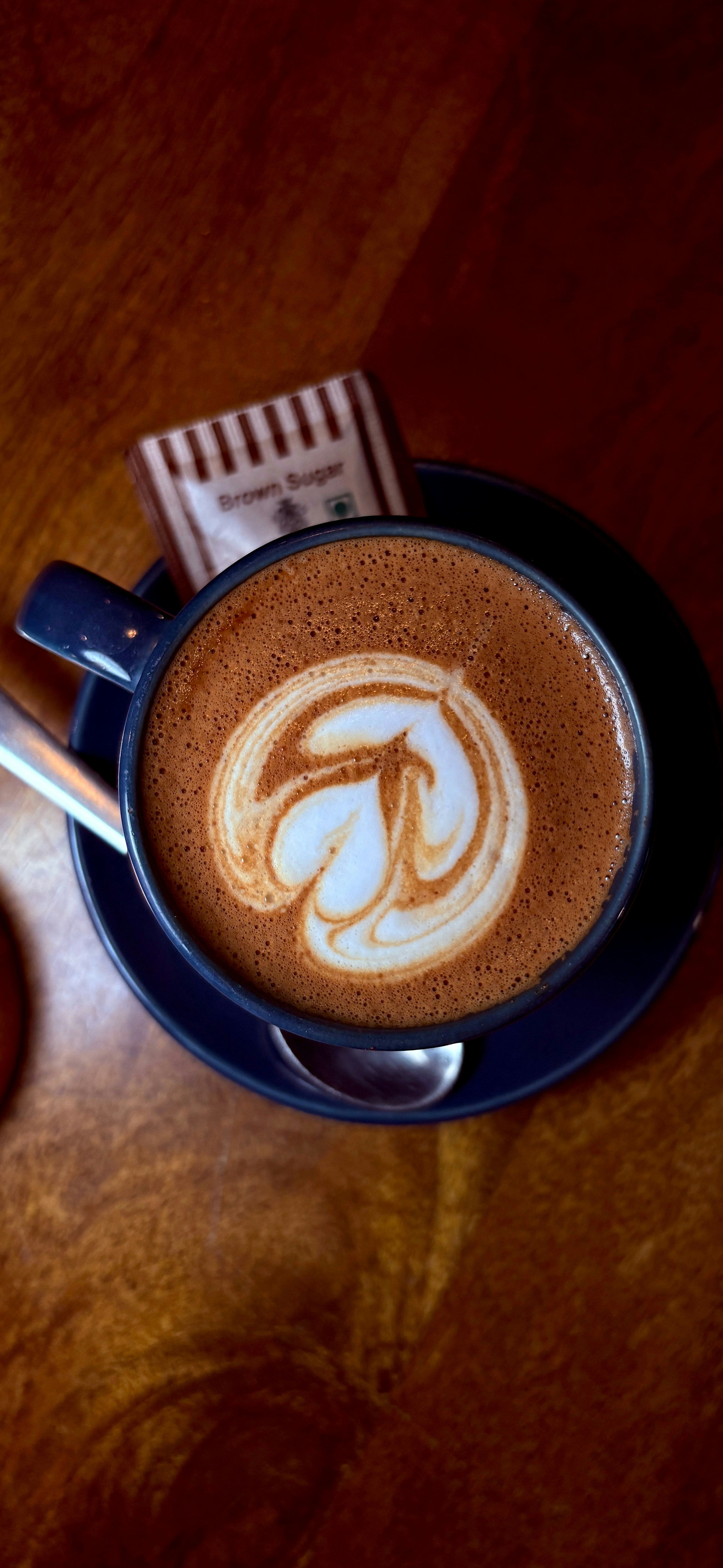 Morning Espresso: Latte Art Nestled in a Deep Blue Cup on Warm Wood