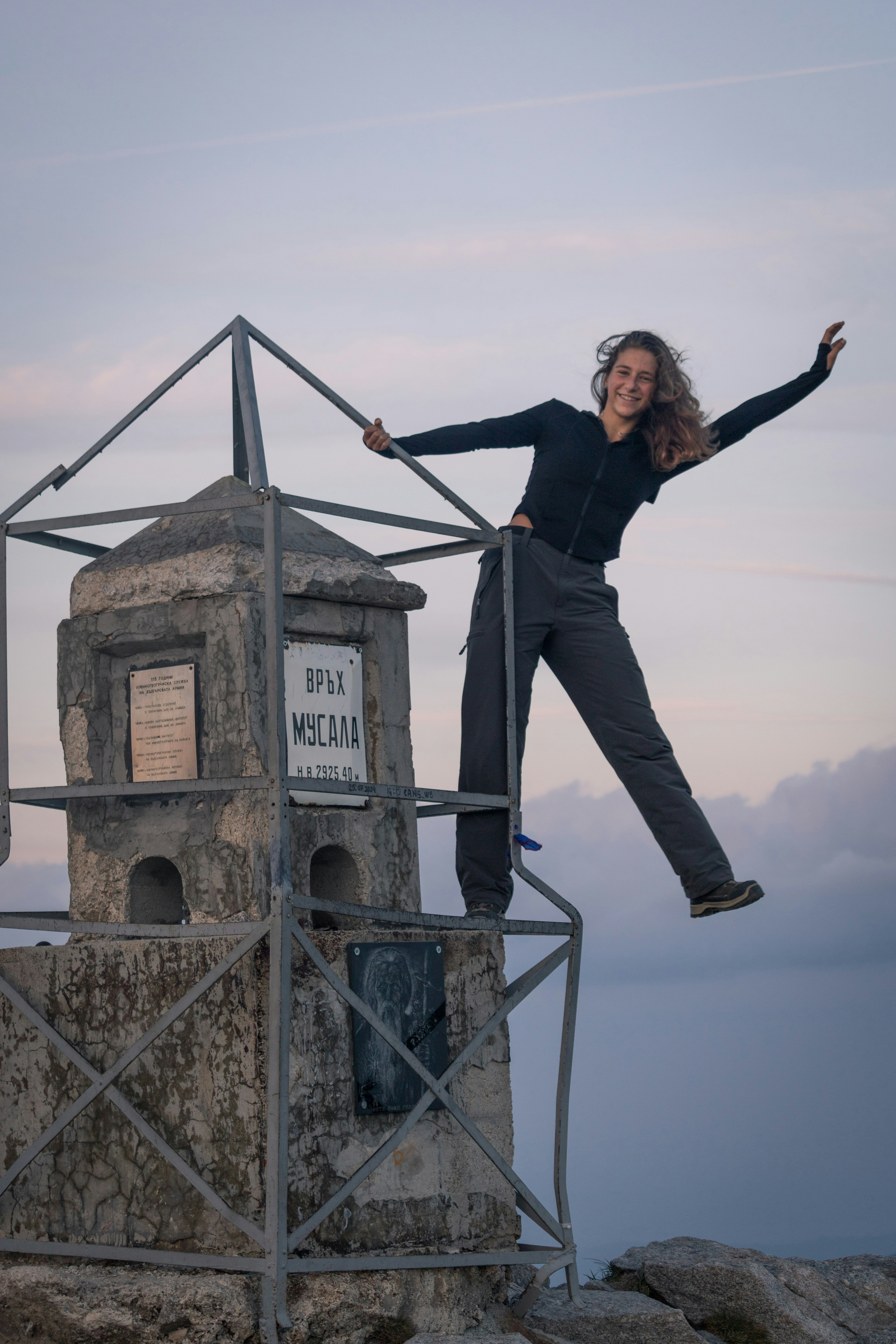 A woman standing on top of a structure on top of a mountain