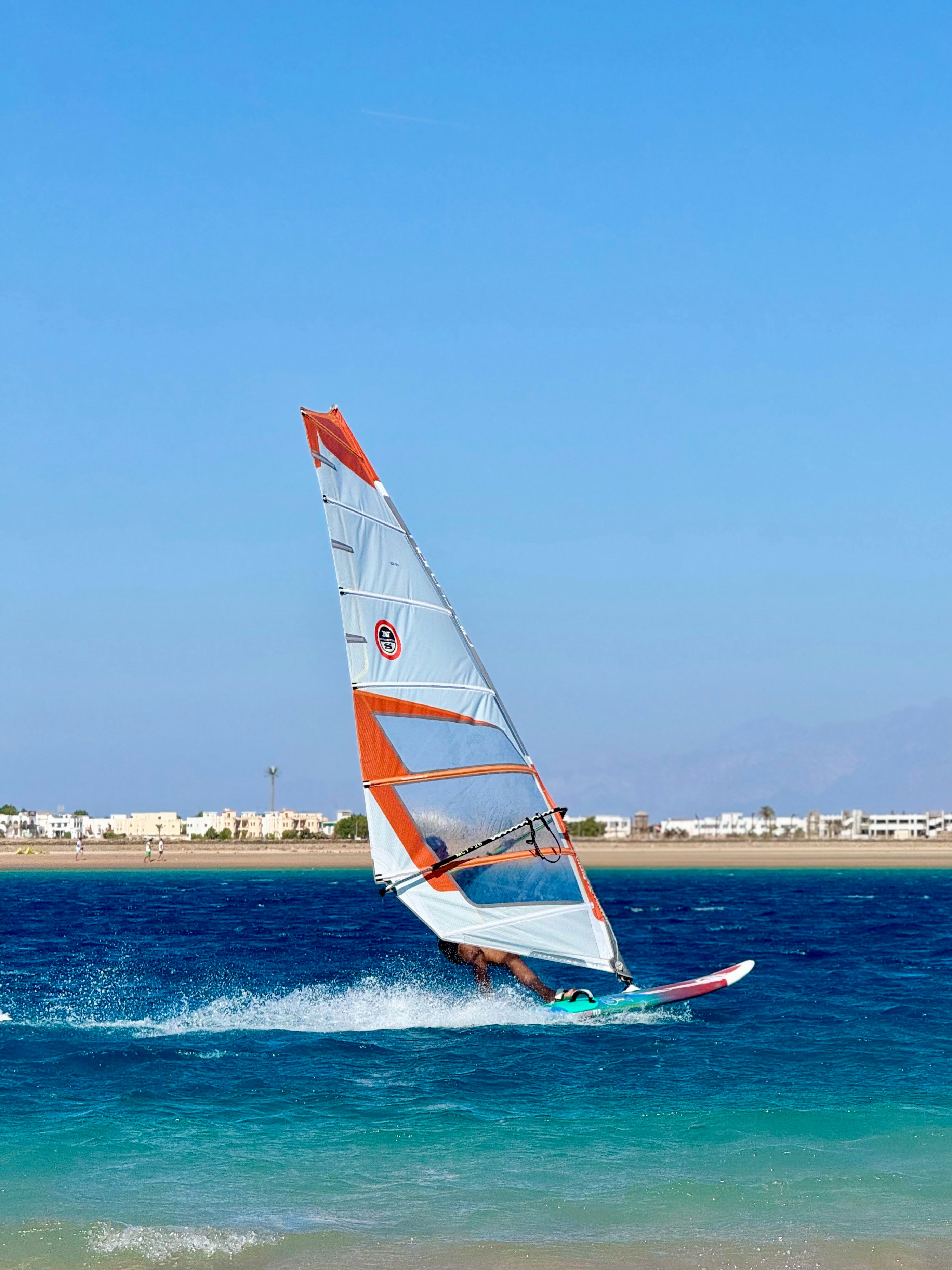 Breeze Rider: Windsurfer Carving Orange Sails Across turquoise Wake