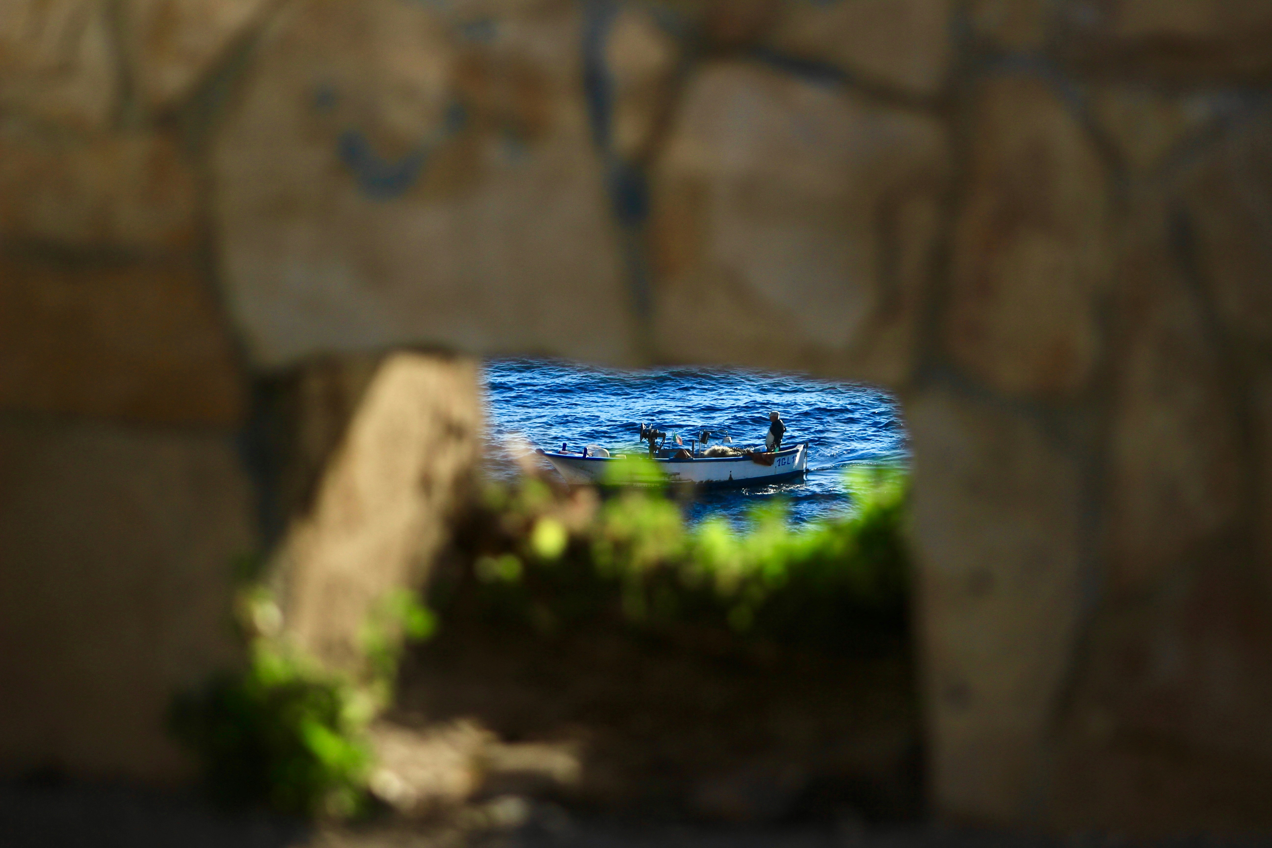 Hidden Harbor View: A Lone Boat Framed by an Ancient Arch