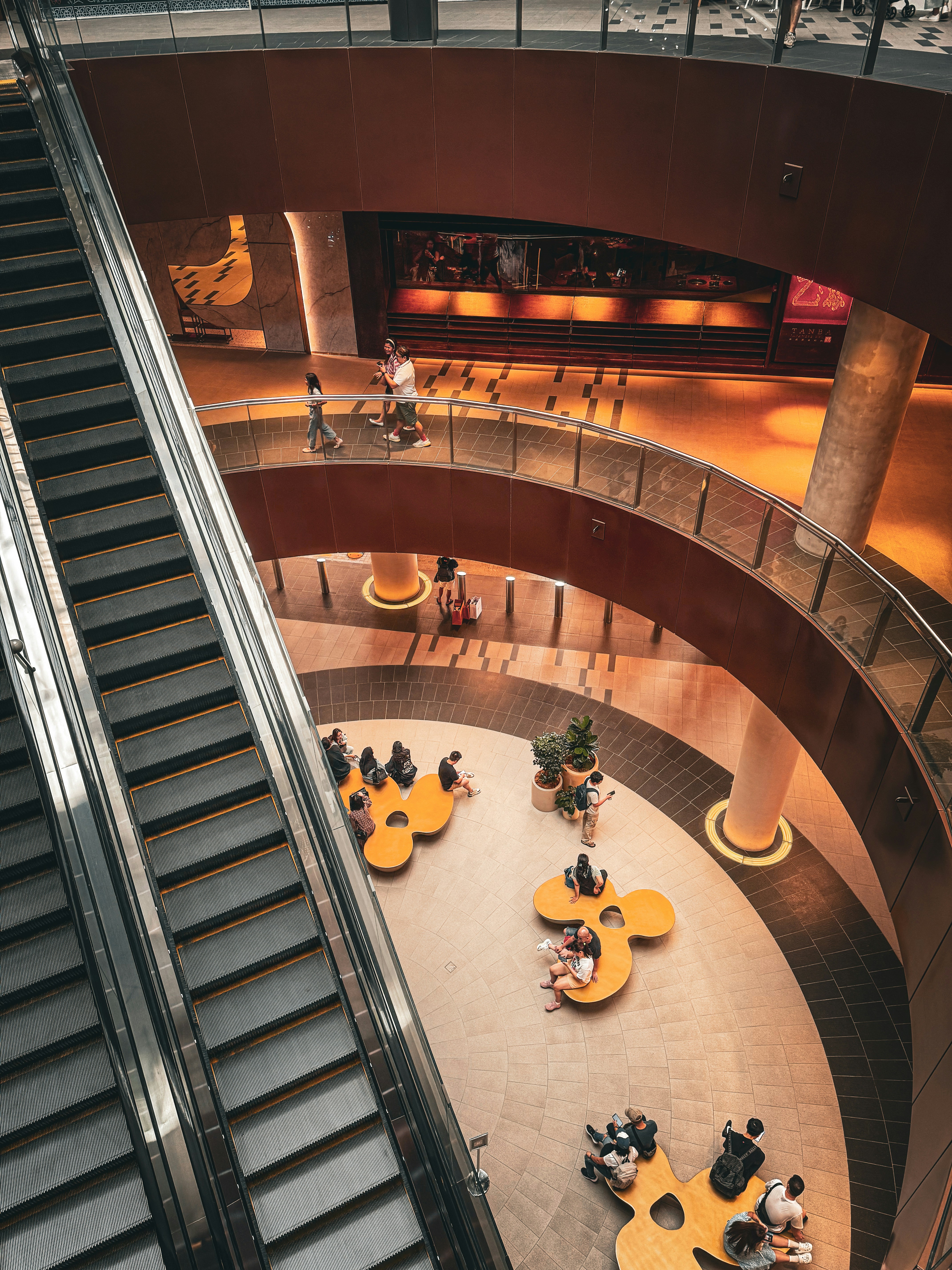 Un grupo de personas sentadas en mesas encima de una escalera mecánica ...