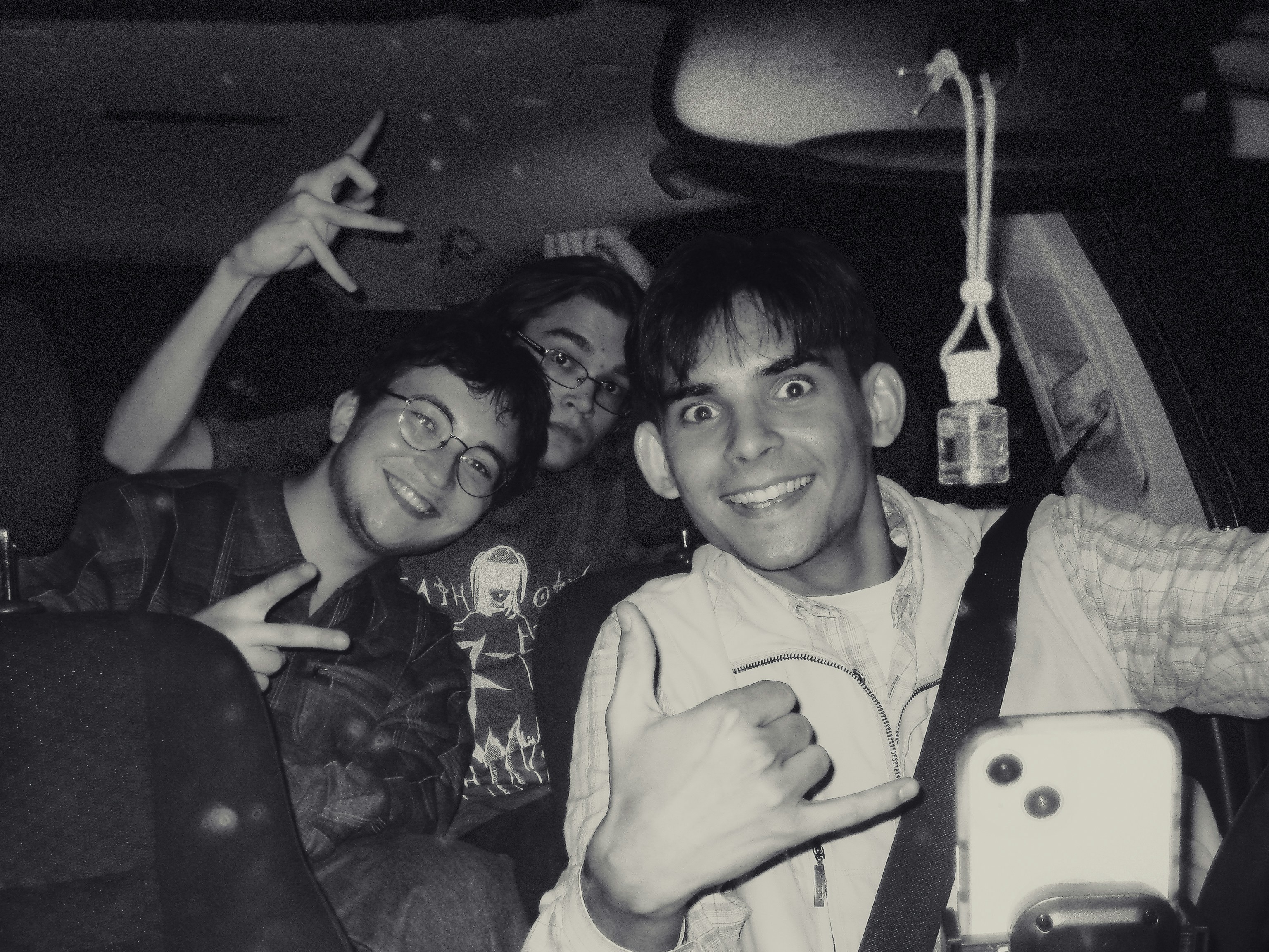 Three friends sharing a joyful moment inside a car at night.