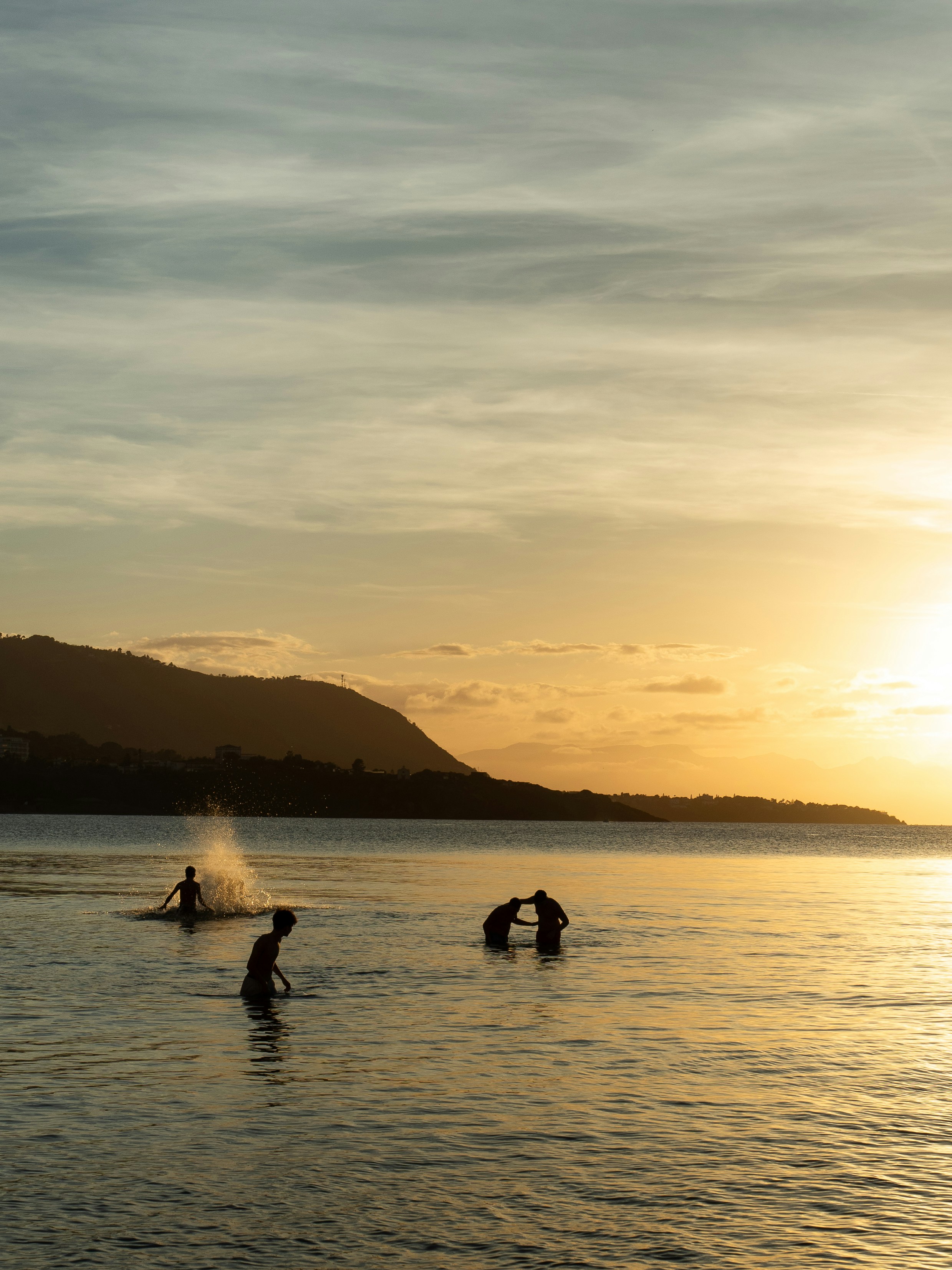 A group of people wading in the water at sunset photo – Free Sicilia ...
