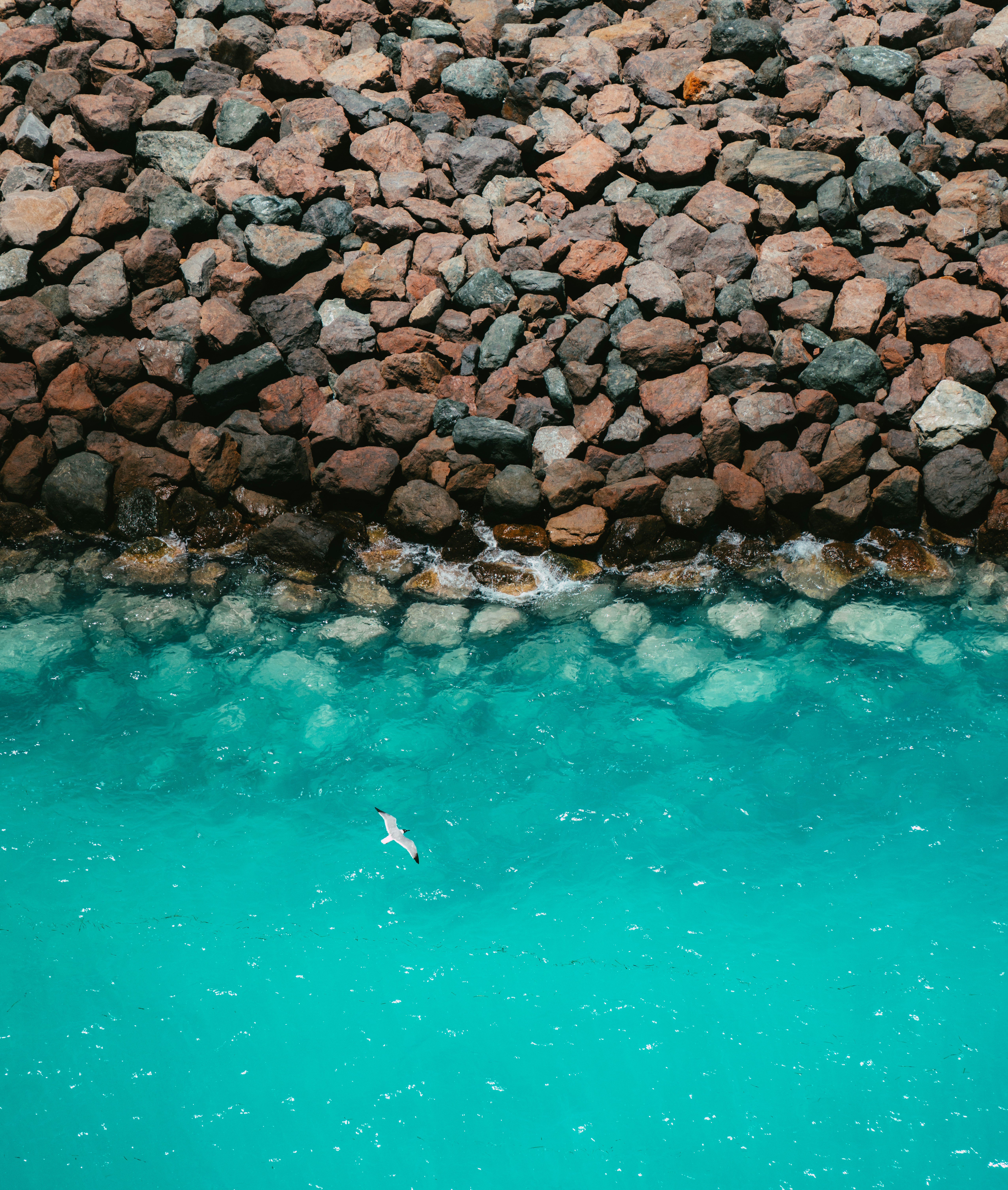 A turquoise shoreline: boulder barrier and sea below